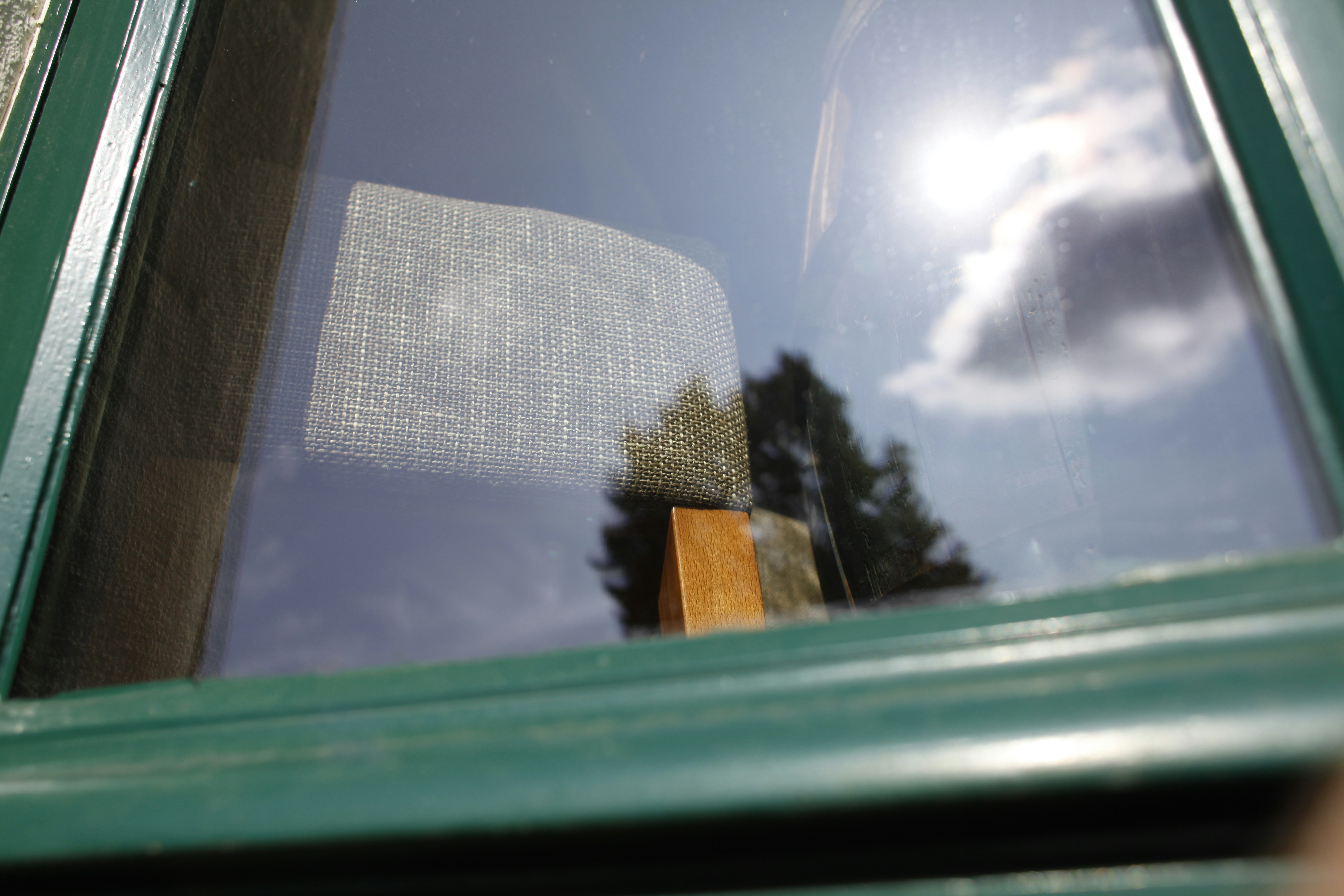 Sunlit Reflection Behind a Green Window Frame
