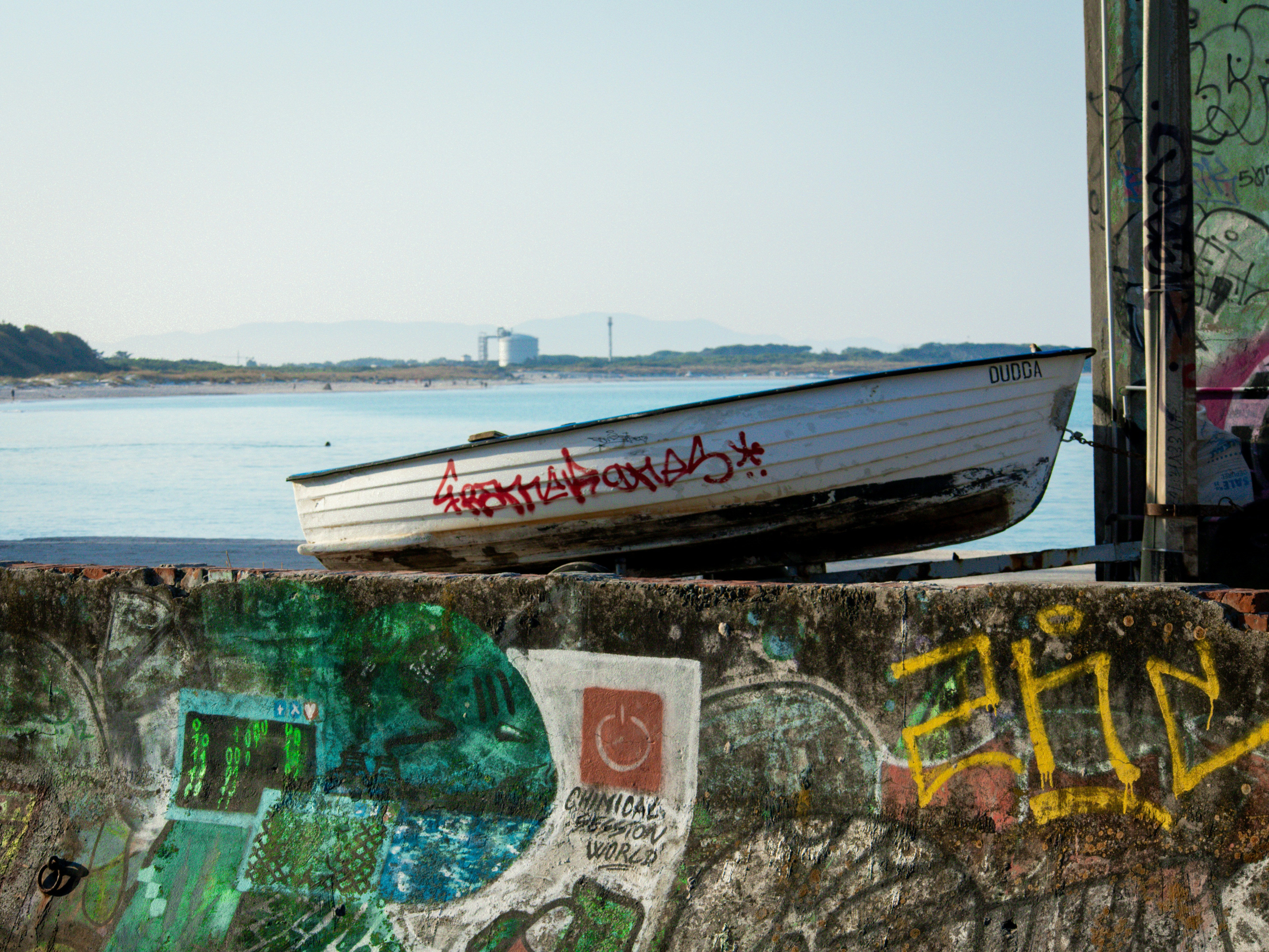 Boat on a Graffiti-Stained Seawall Over a Tranquil Tide