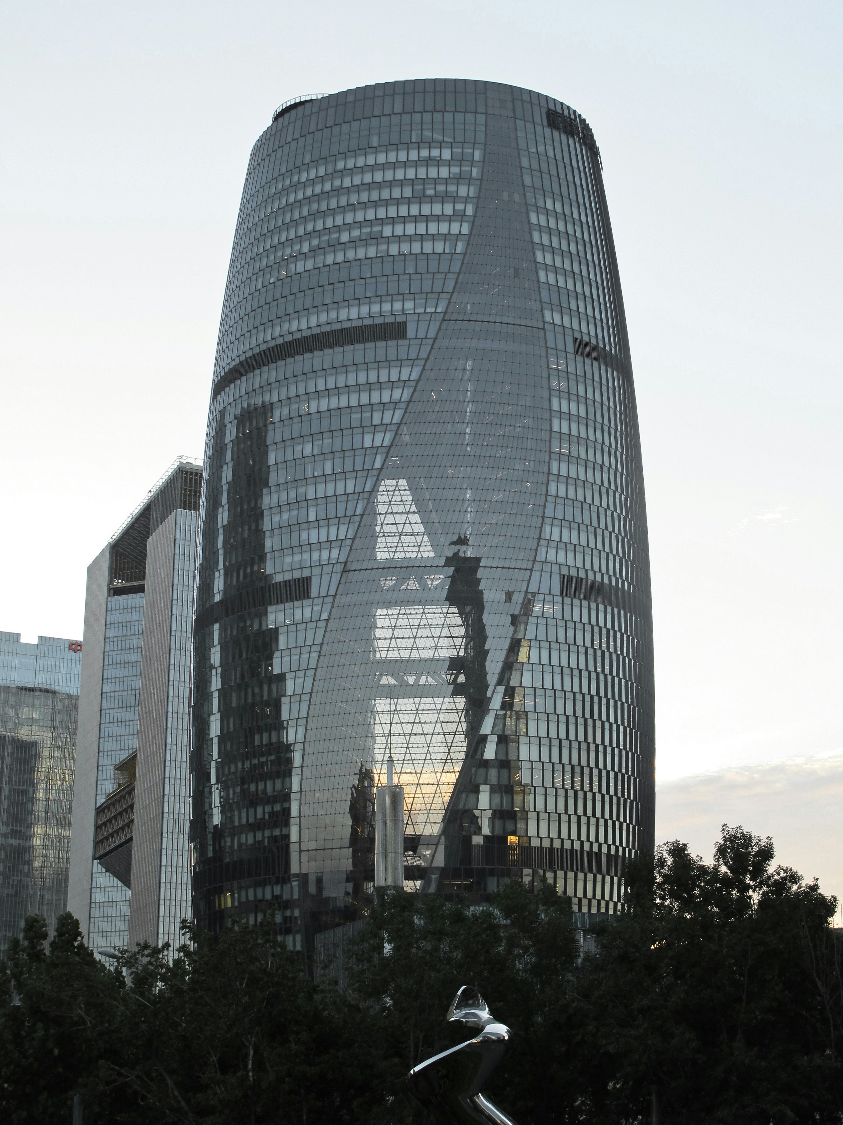 A tall glass building with a sculpture in front of it photo – Free ...