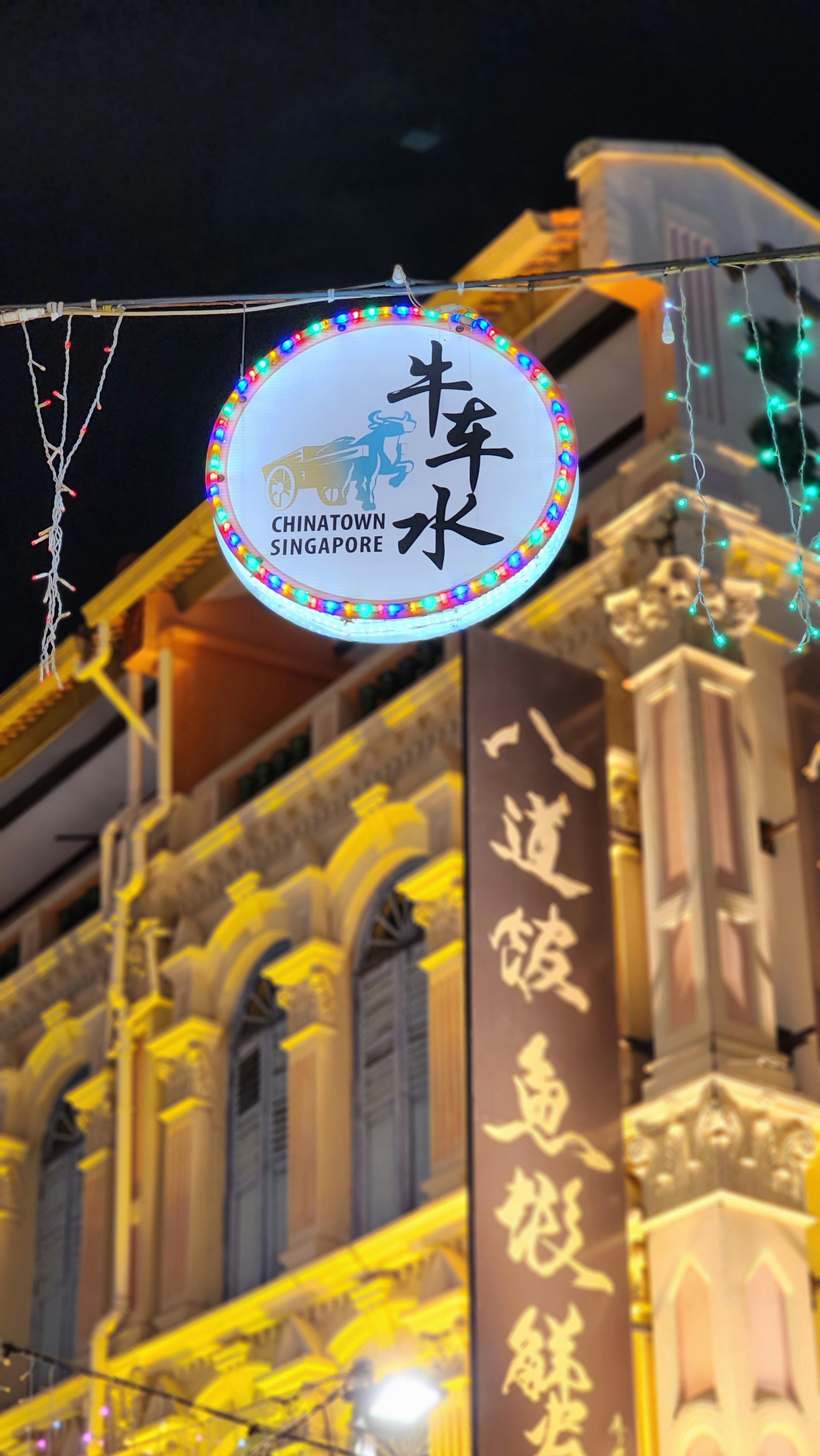 Neon Halo Over Chinatown Singapore: Circular Sign Illuminates the Historic Facade at Night
