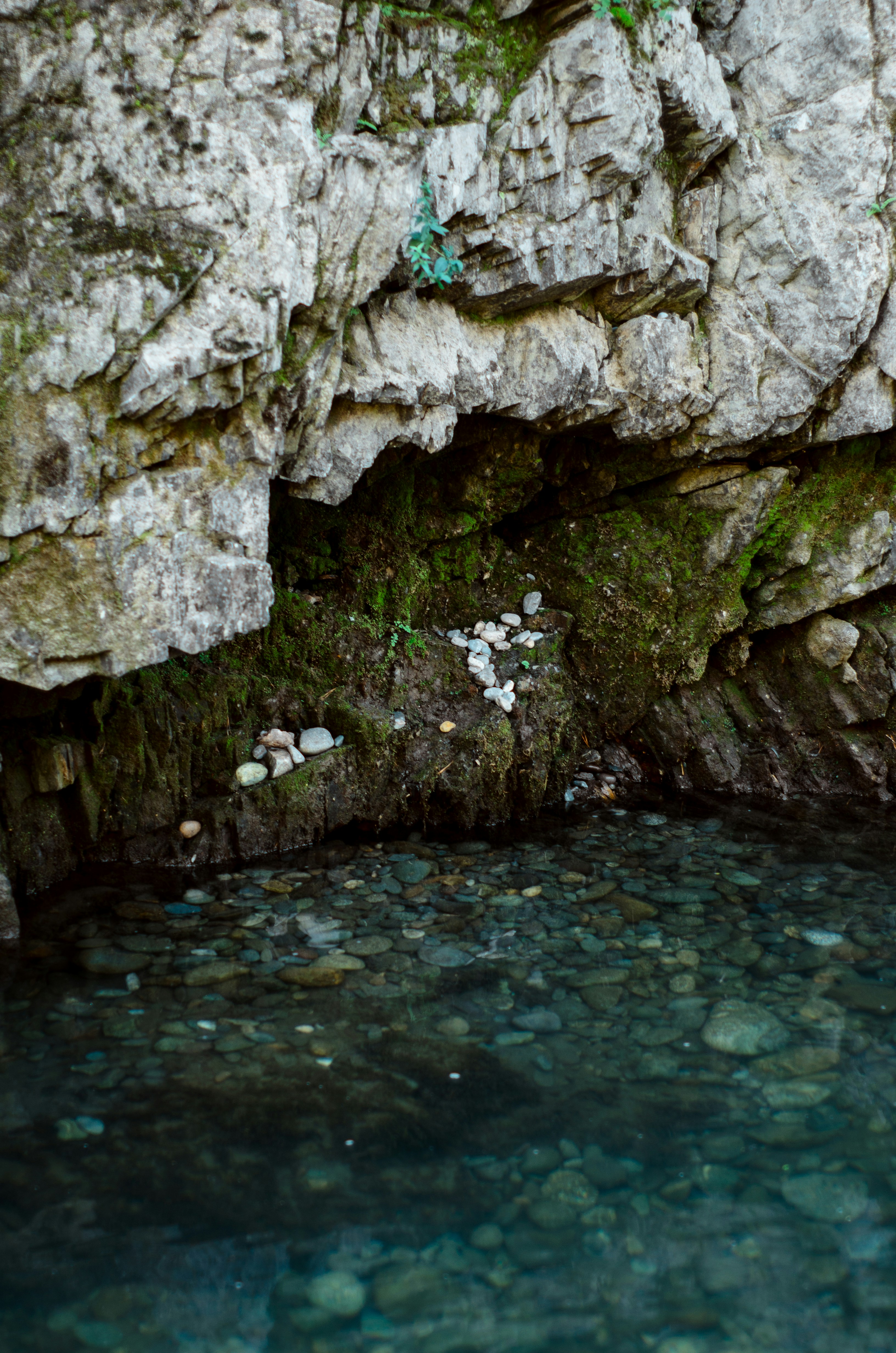 Moss-Draped Limestone Over a Glassy Cove: Pebbles, Moss, and Turquoise Depths
