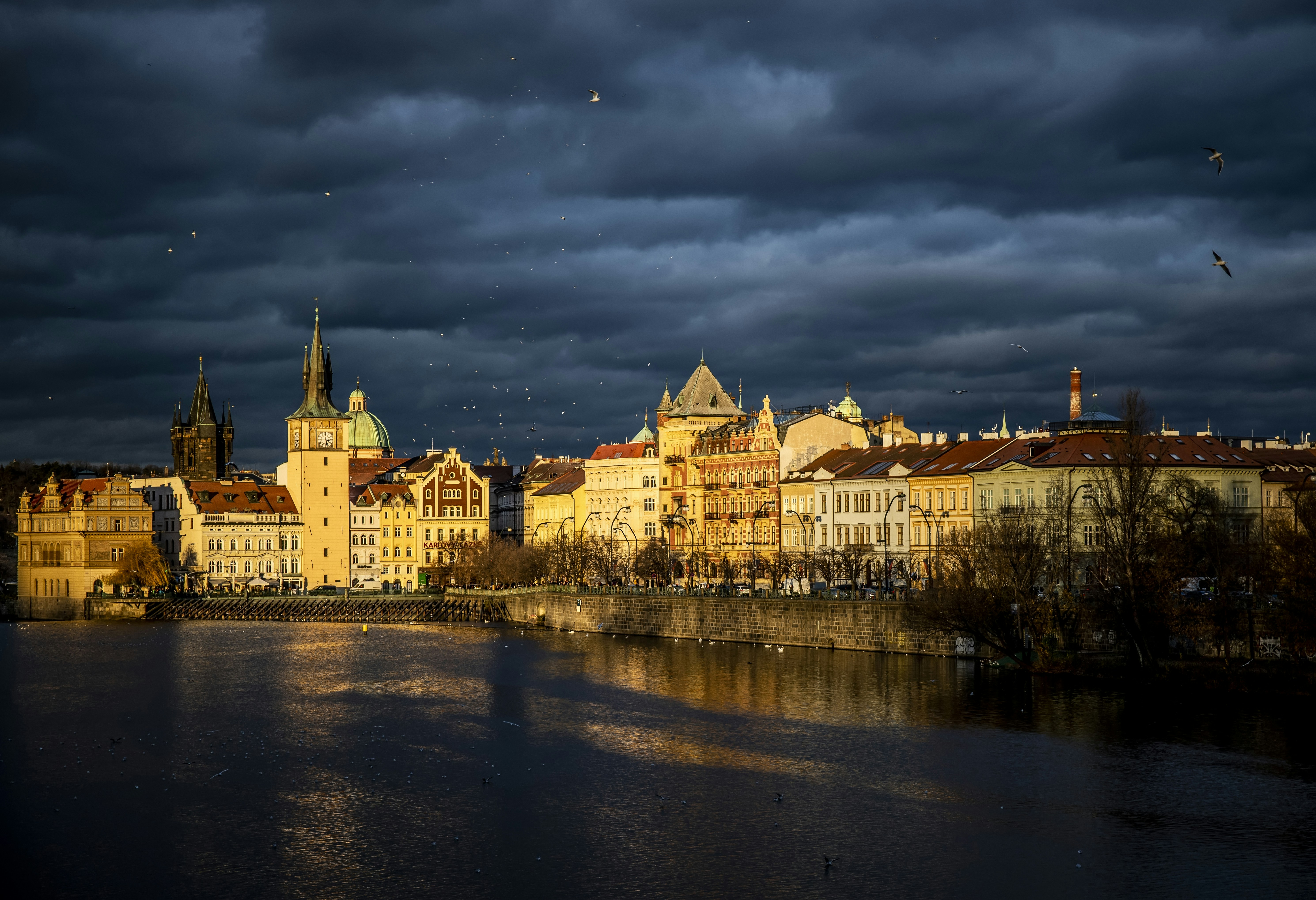 Golden Hour Riverside: Historic Cityscape Under a Stormy Sky