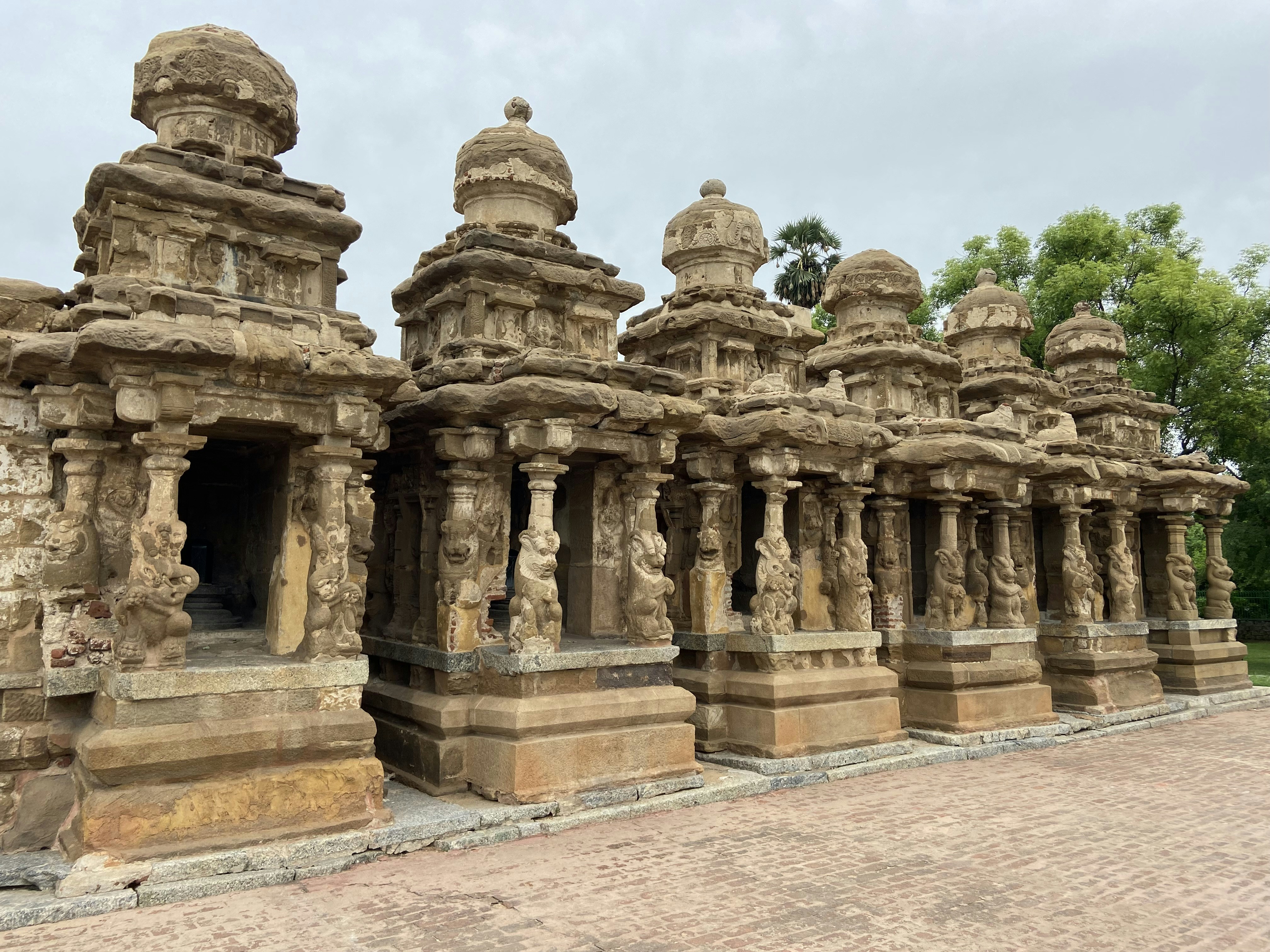 A row of stone statues sitting on top of a sidewalk photo – Free India ...