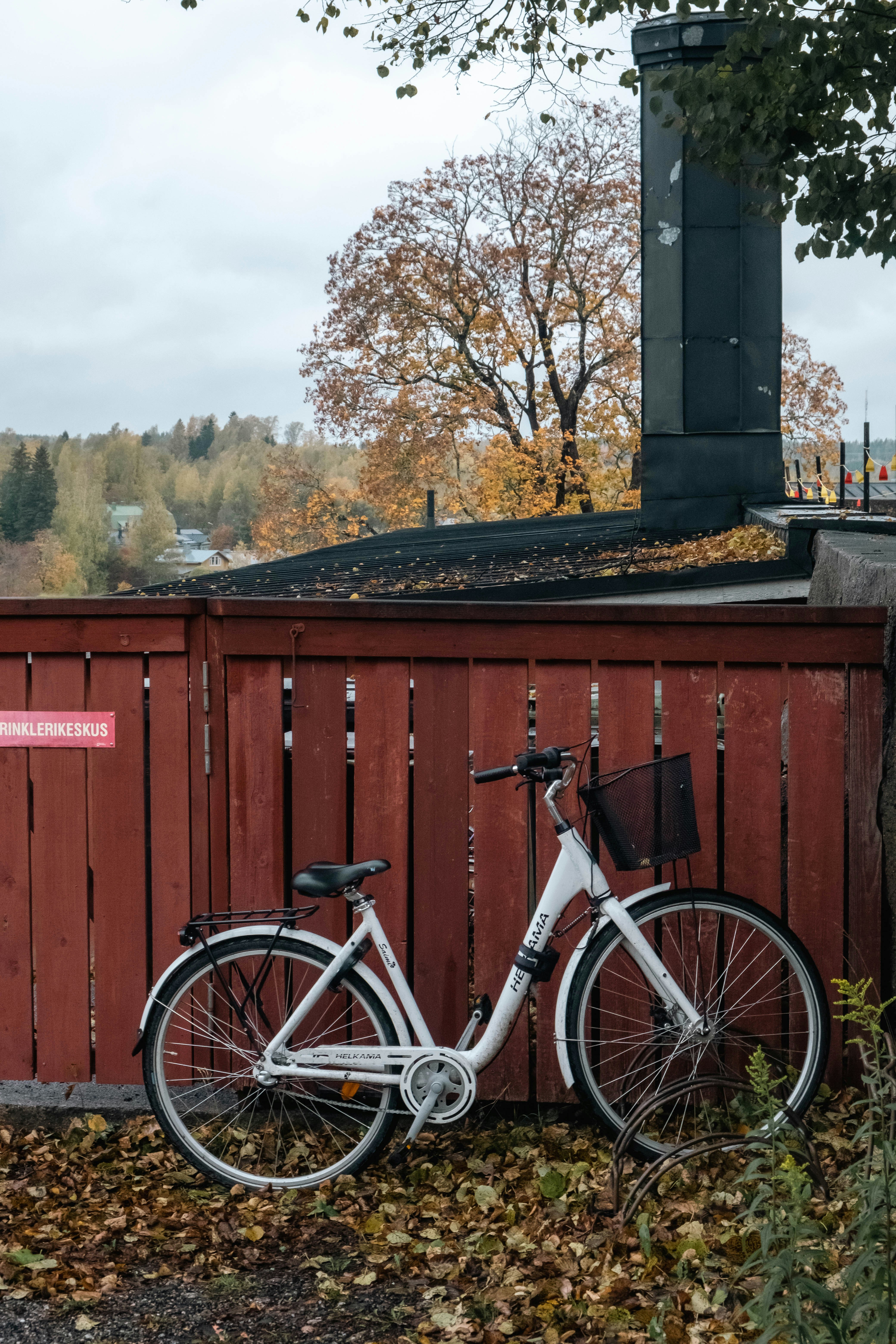 Autumn Quiet: White City Bicycle by a Red Fence in Soft Daylight