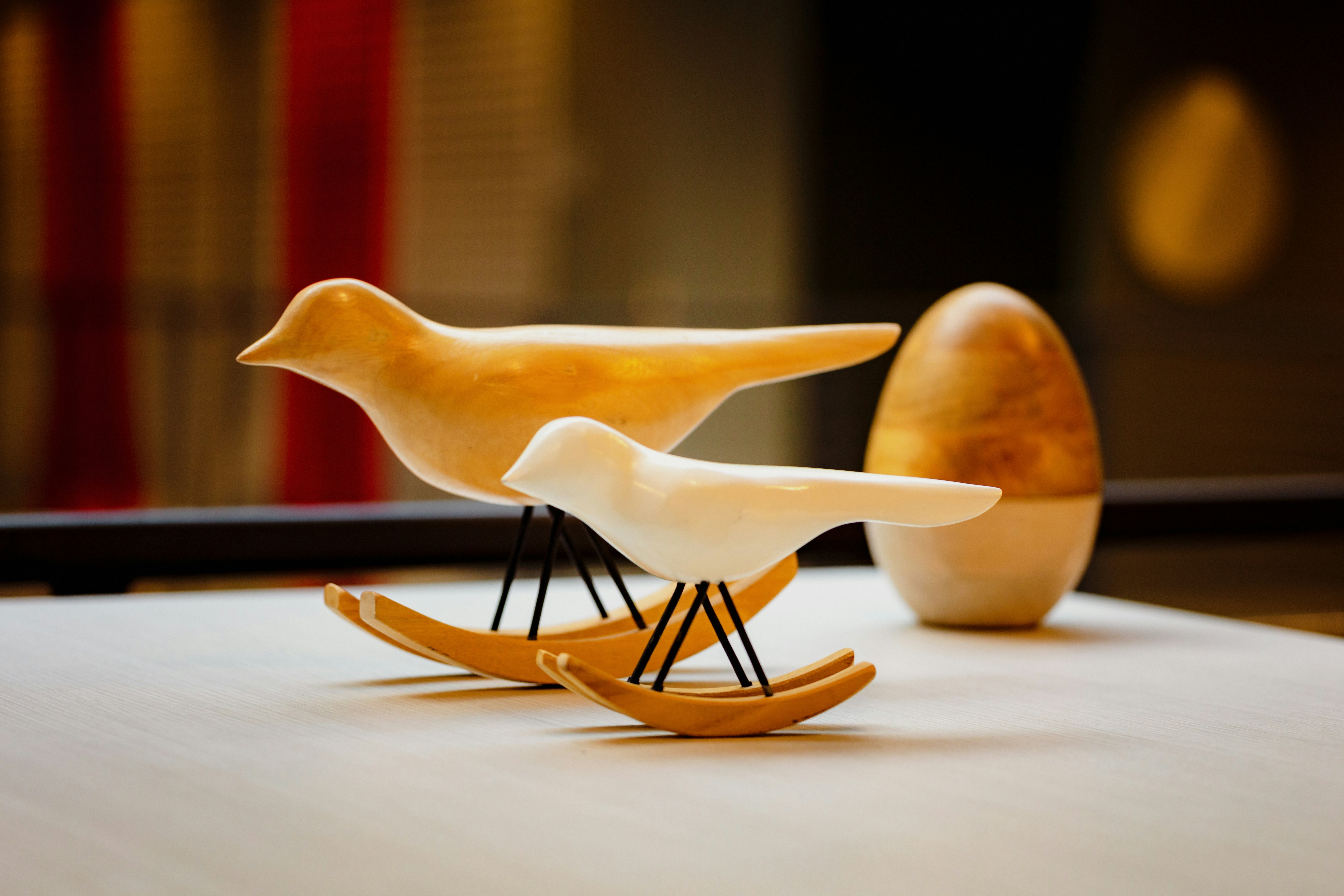 Sculpted Silence: White Bird on a Curved Stand Under Warm Studio Light