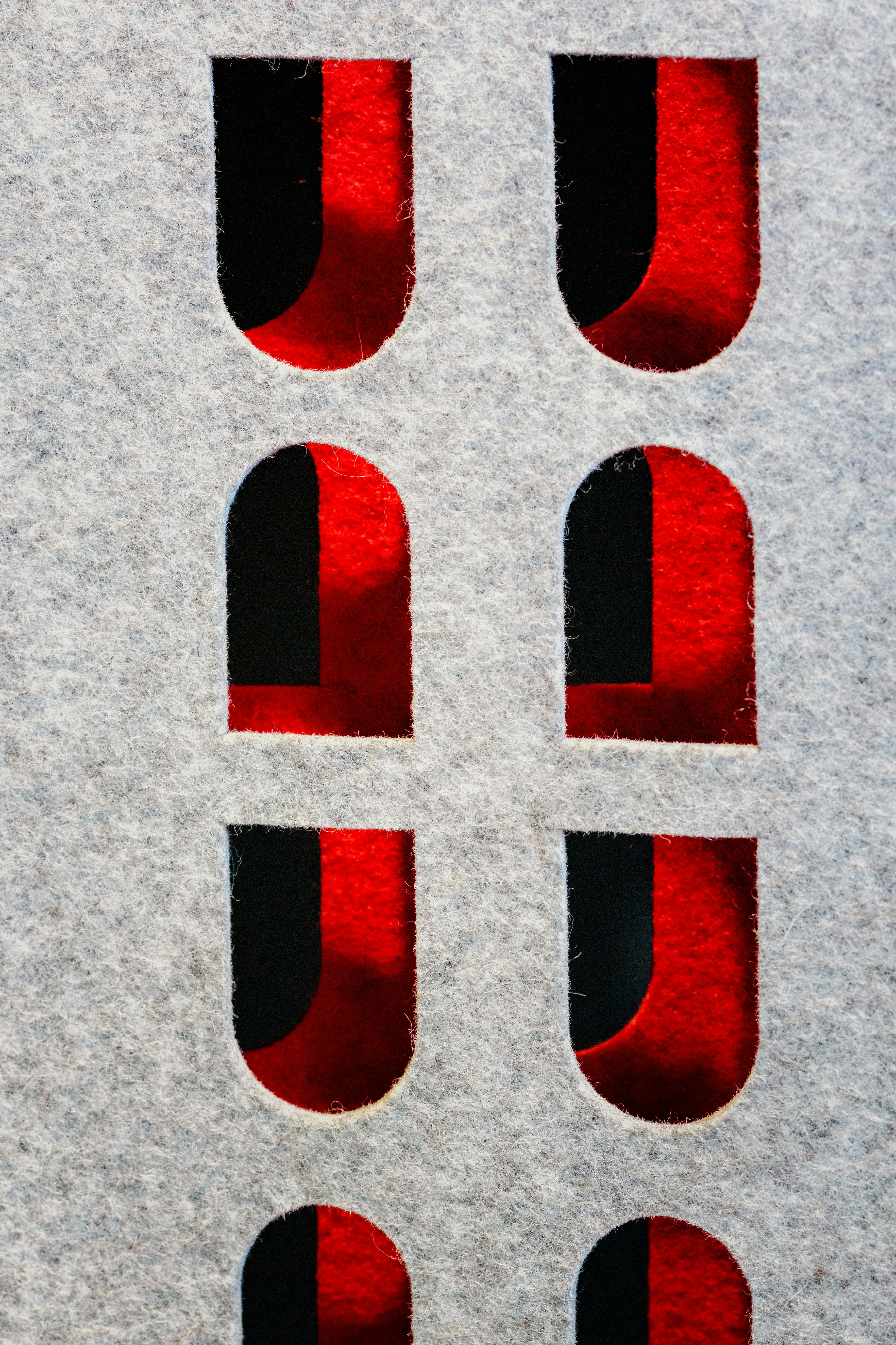Red Crescent Grid: a precise pattern of curved openings on a gray canvas