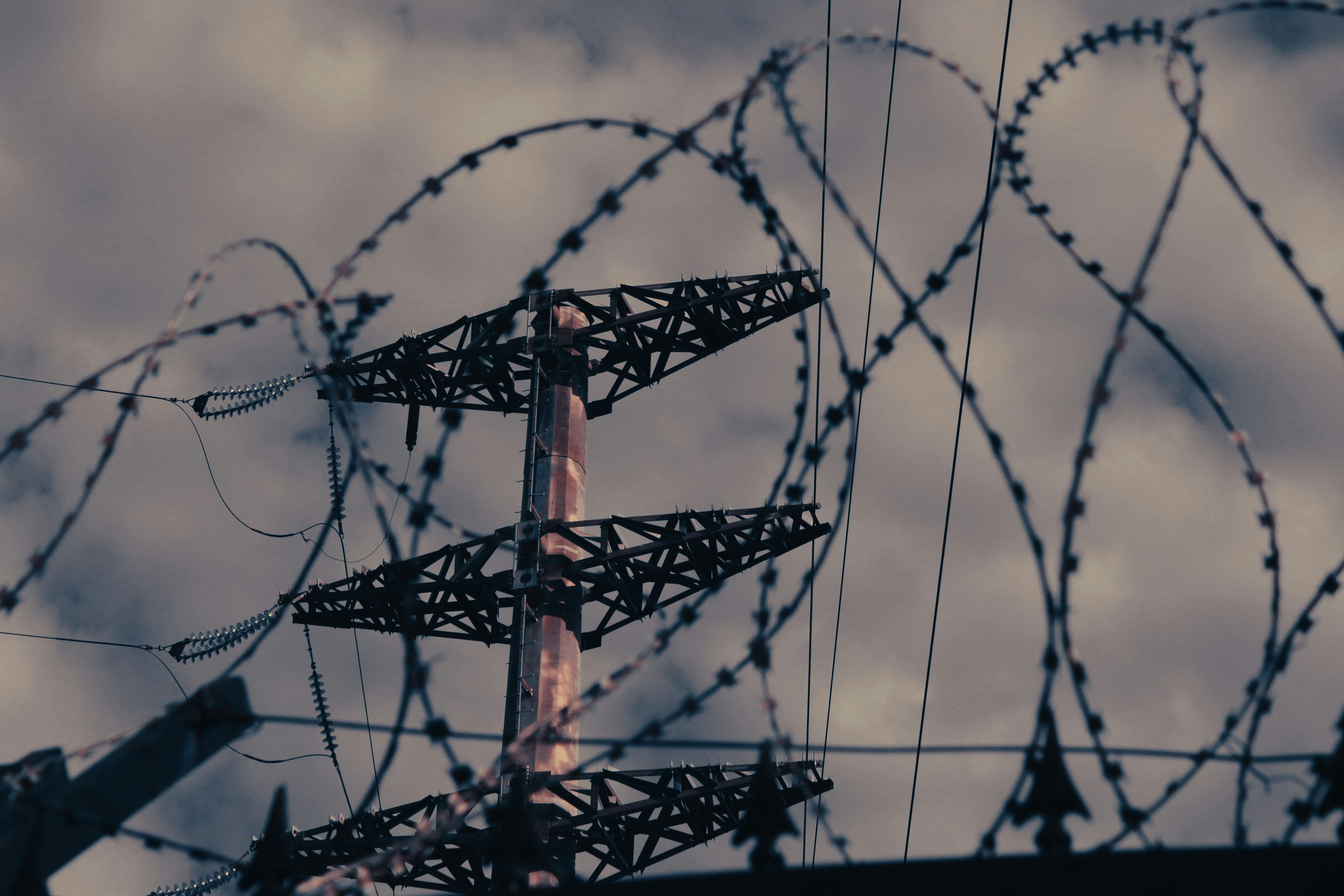 Barbed Frontier: A Lattice Tower Framed by Coil and Cloud