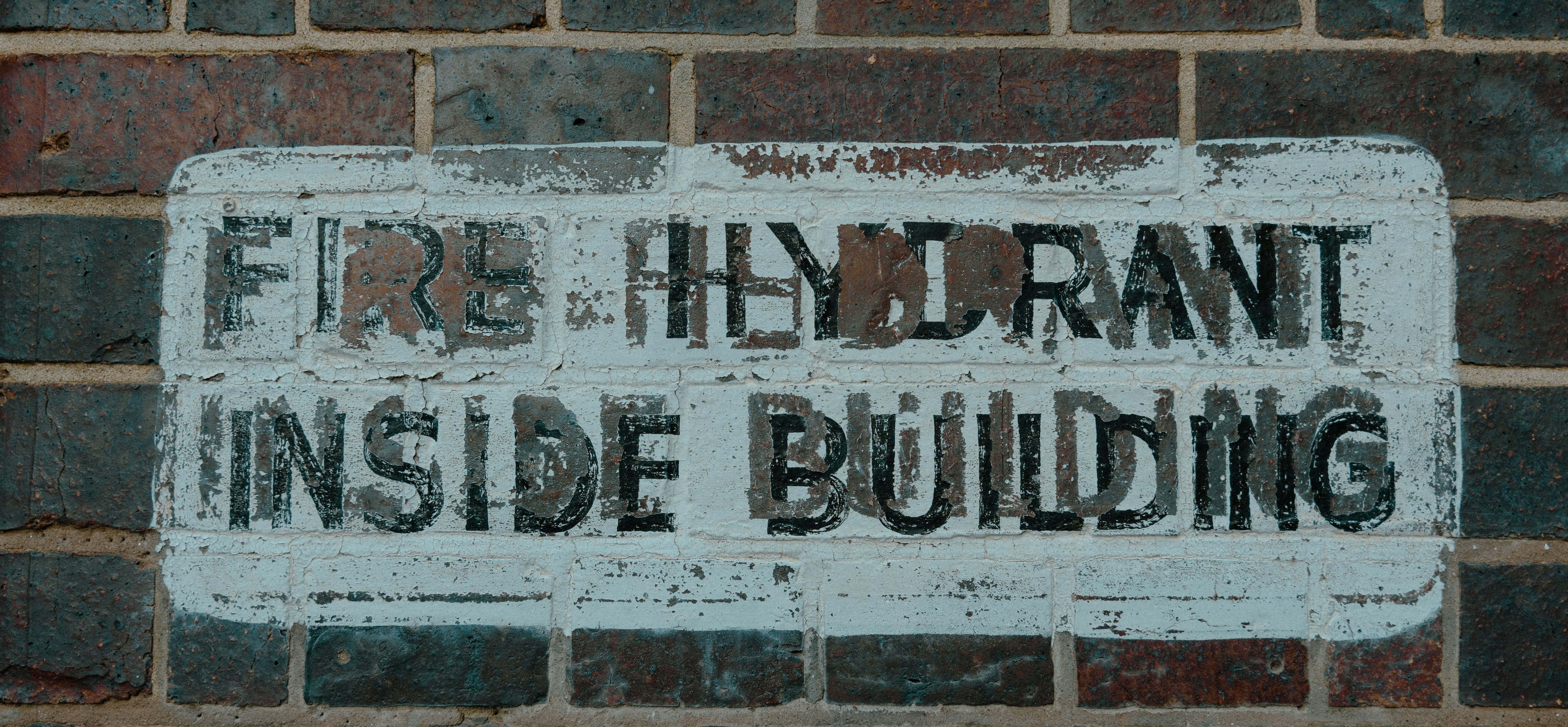 A sign on a brick wall that says fire hydrant inside building photo ...