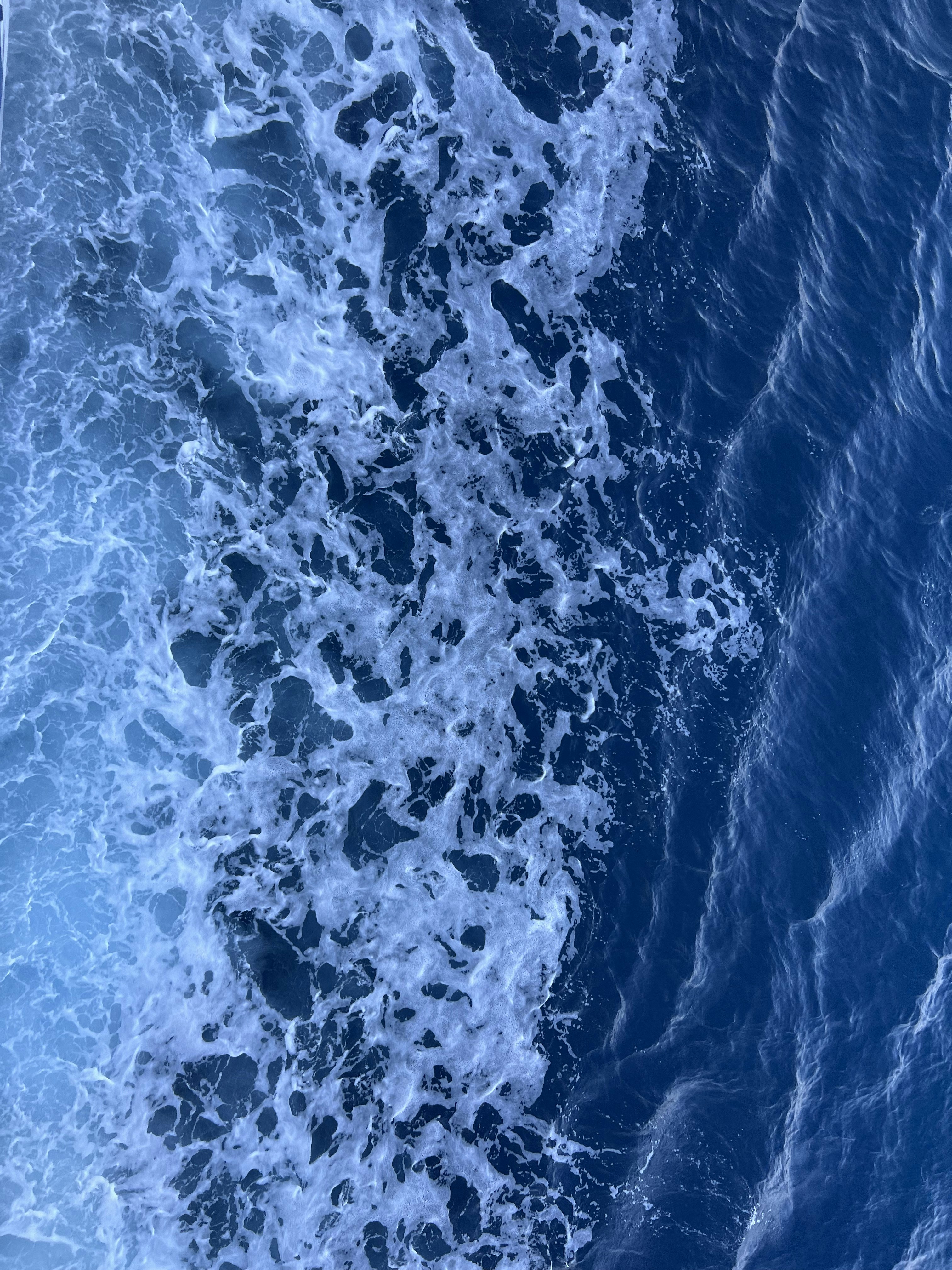 Aerial Contrast: White Foam Carves a Blue Ocean Divide
