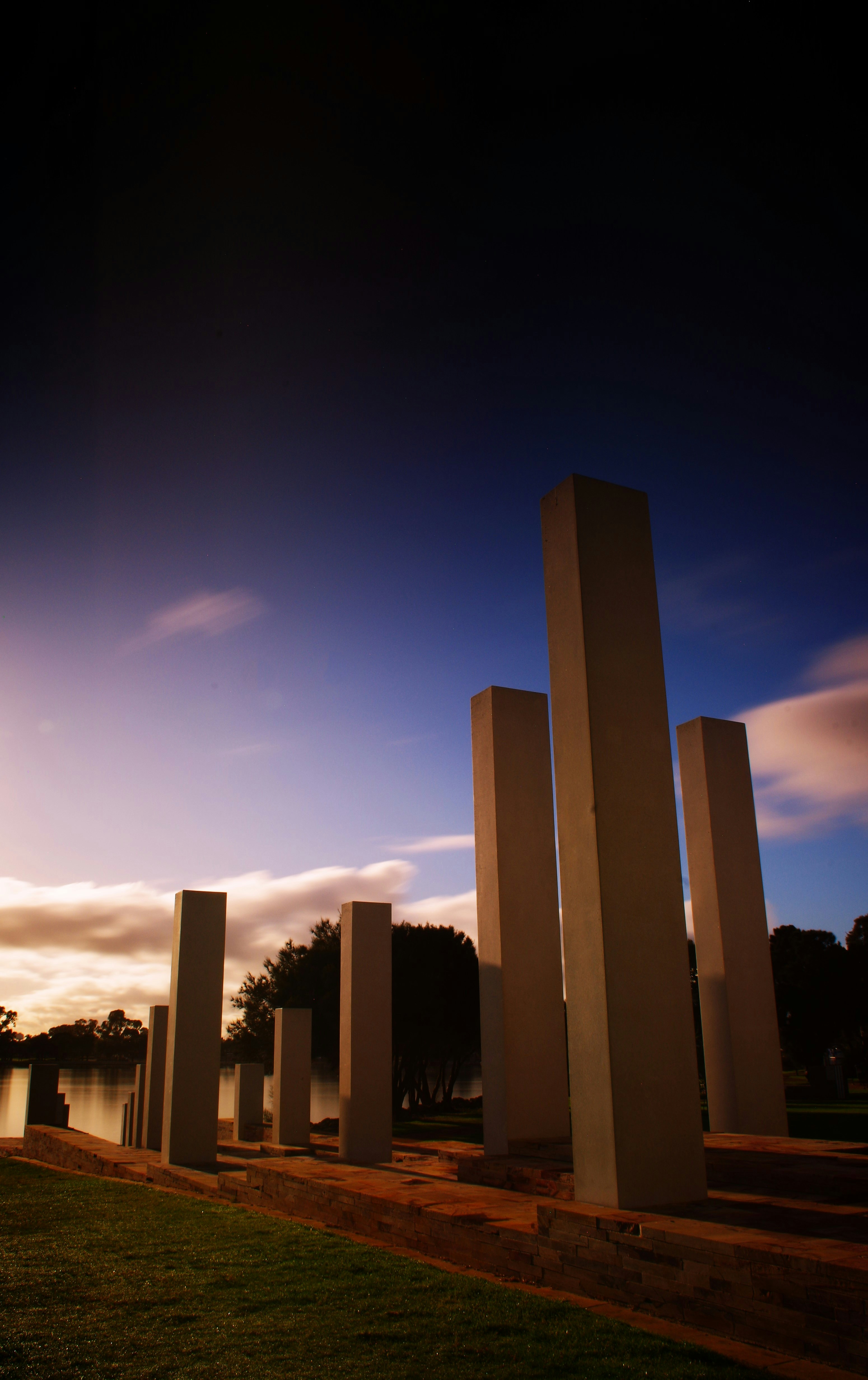 A group of tall white pillars sitting on top of a lush green field ...