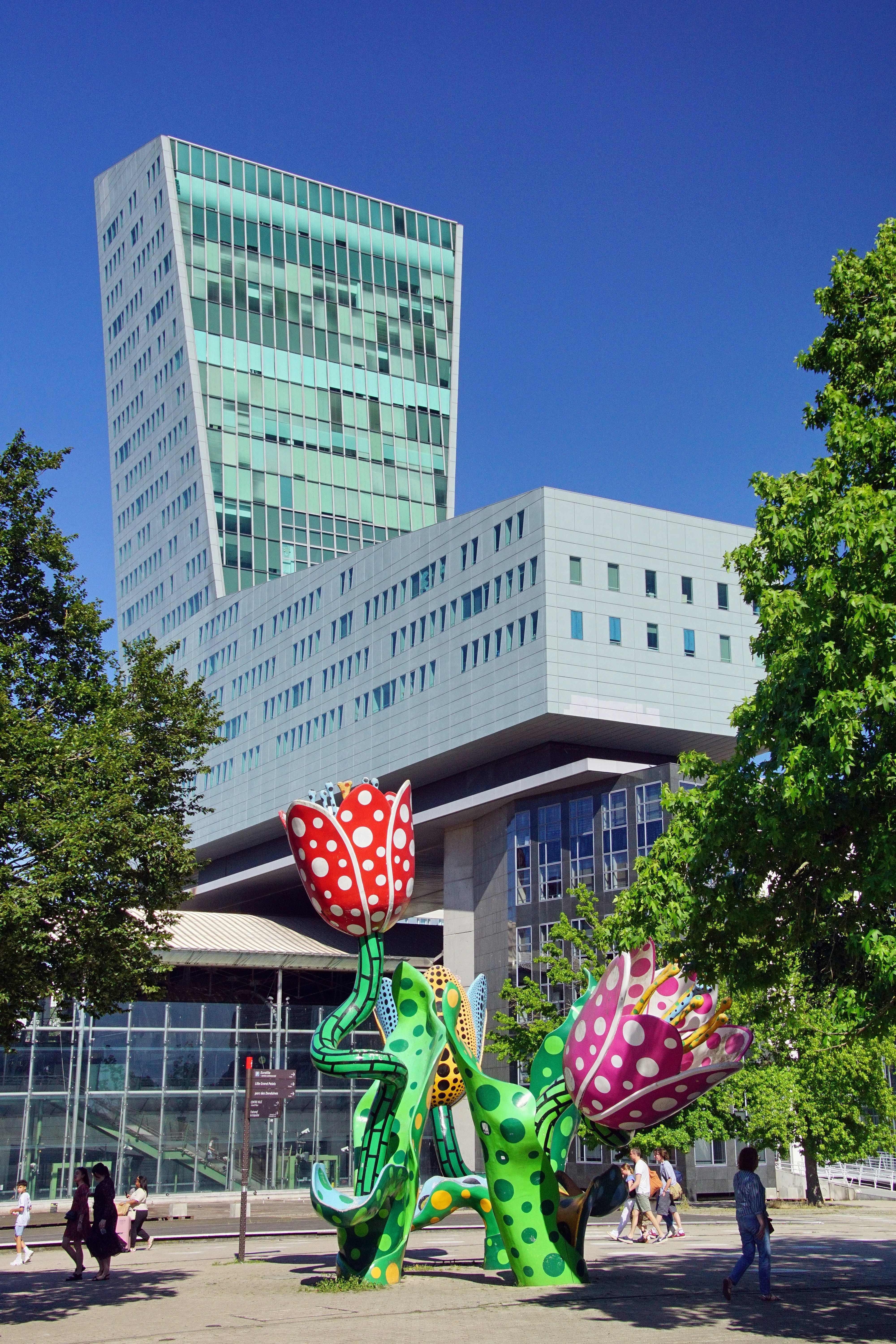 A modern, L-shaped office building of the Euralille with a funny sculpture in the forefront in Lille, France.