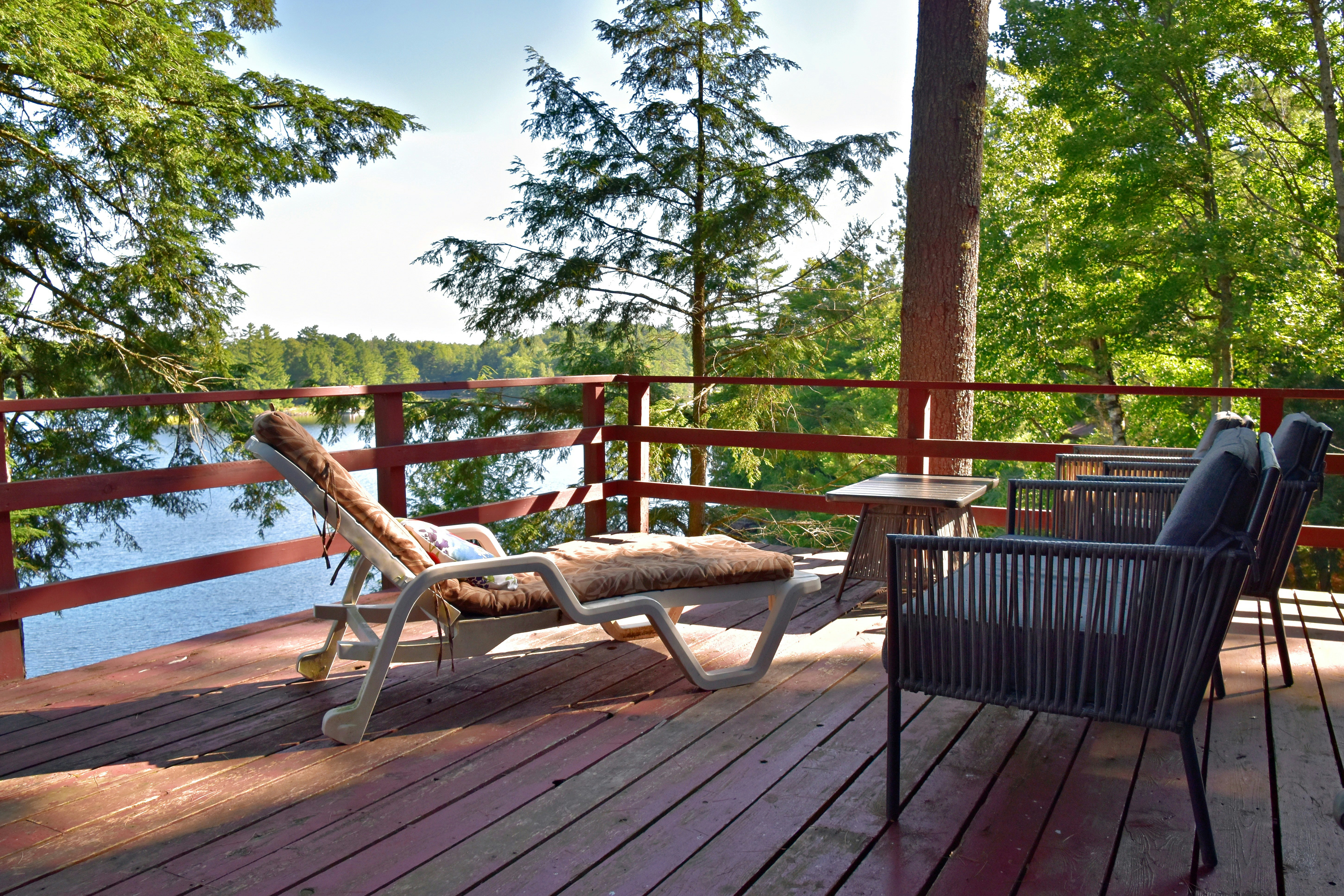 A chair and a table on a deck overlooking a lake photo – Free Gooderham ...