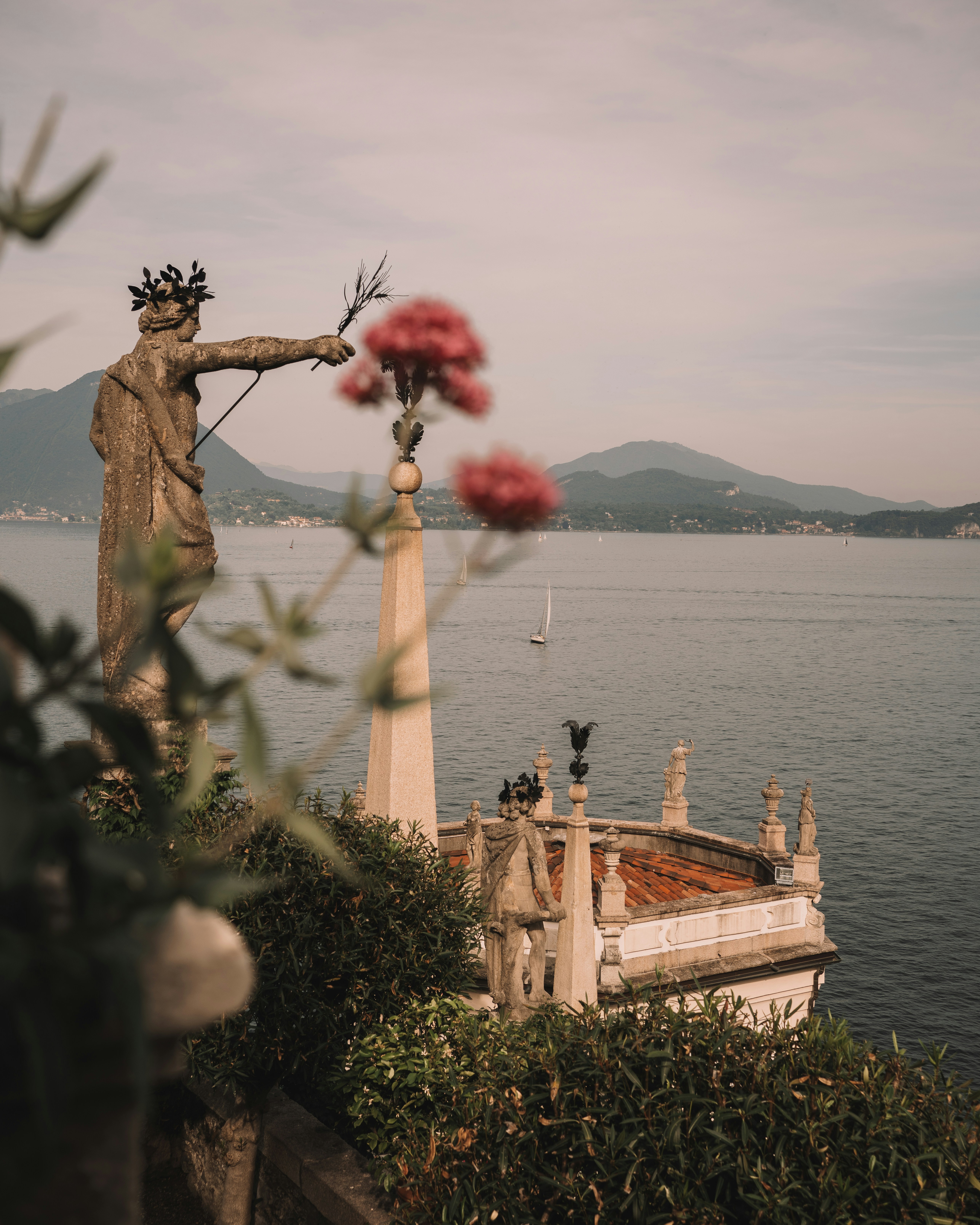 The Reach Across the Lake: A lakeside statue extends toward distant sails