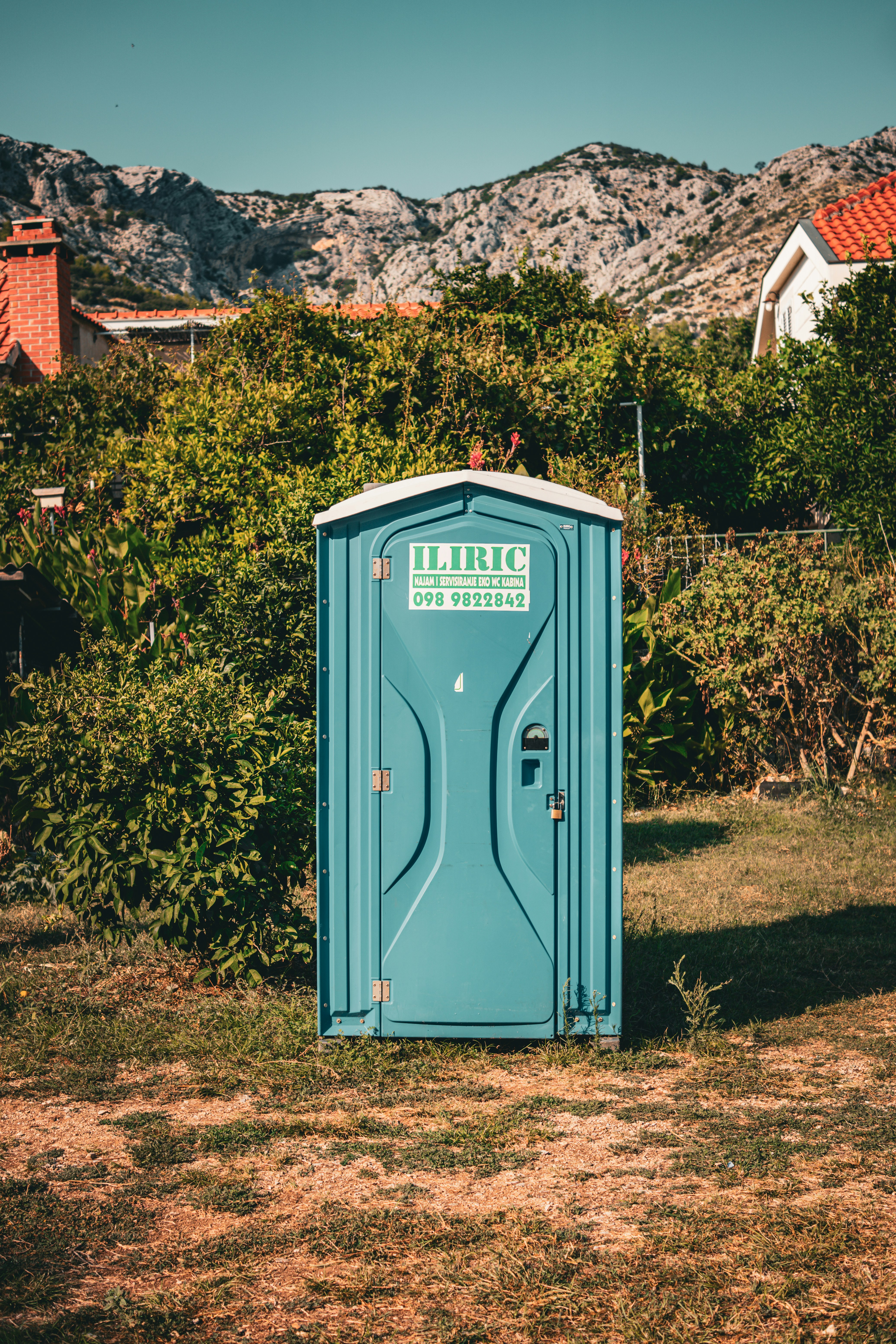A blue portable toilet sitting in the middle of a field photo – Free ...