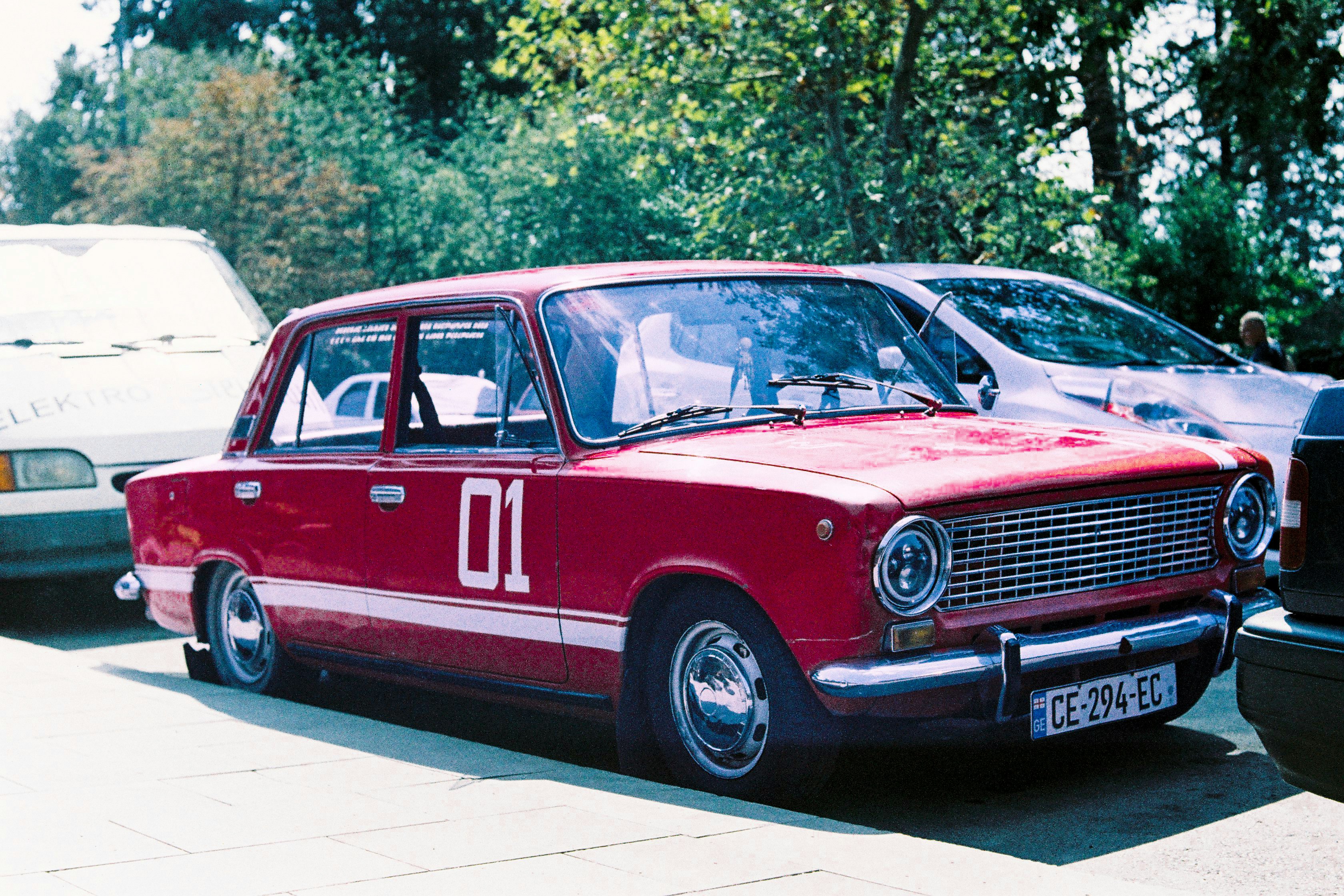 Race-Ready Flame: Classic Red Rally Car on a Sunlit Street