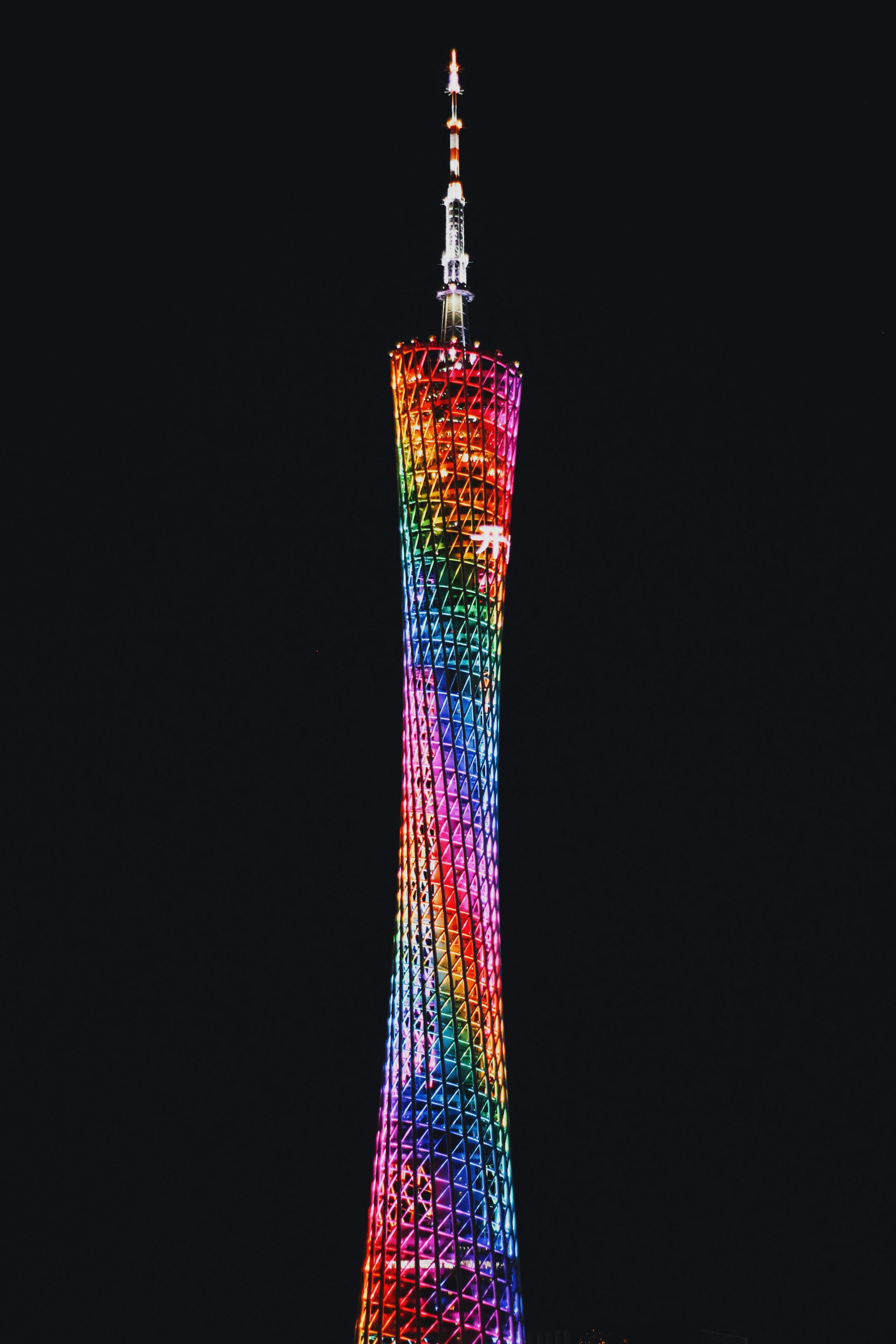 The Guangzhou Tower radiates a vibrant spectrum of colors against the night sky, showcasing its unique architectural design.