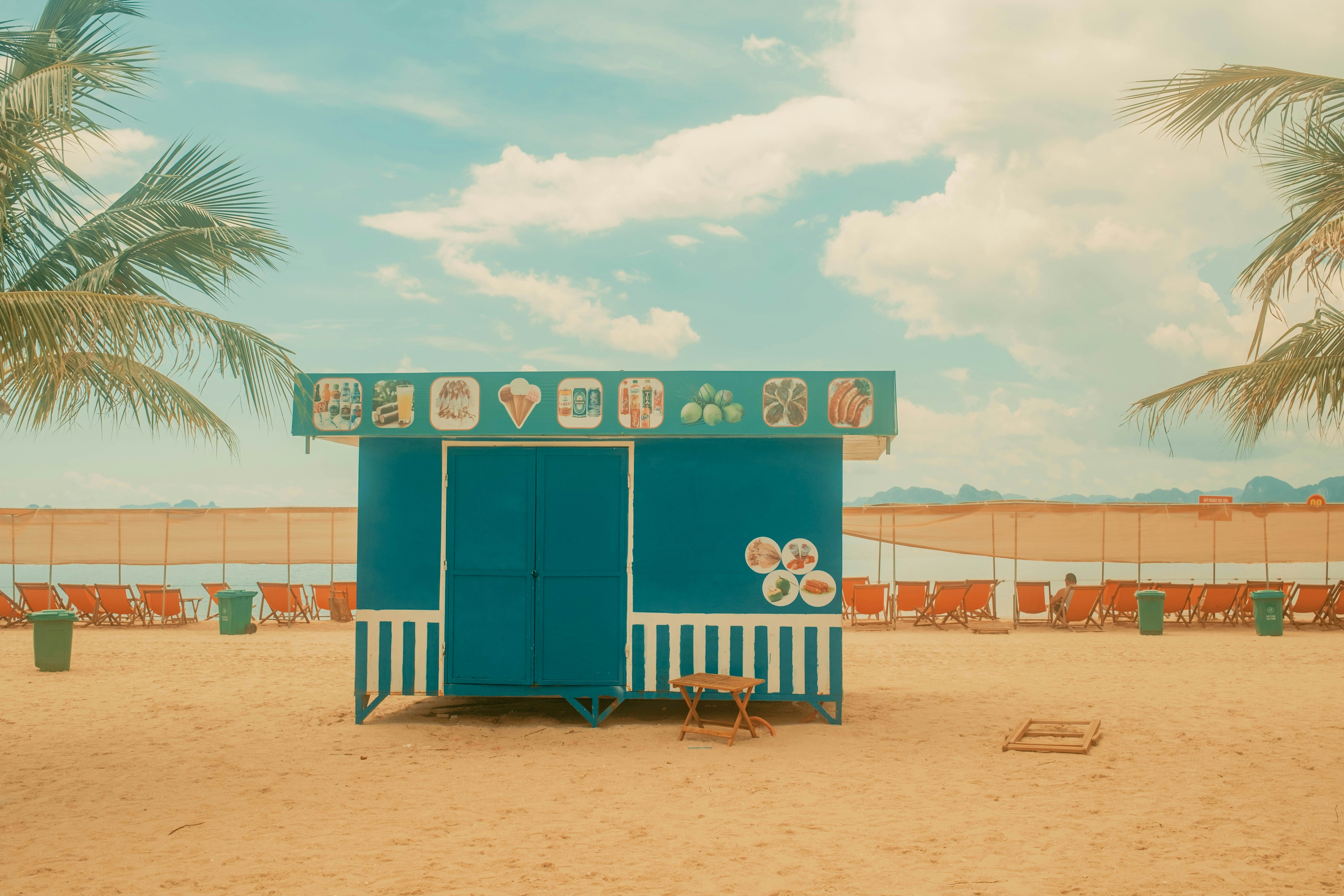 Turquoise Beach Shack Stands Centered Amid Palm Shadows on a Quiet Shore