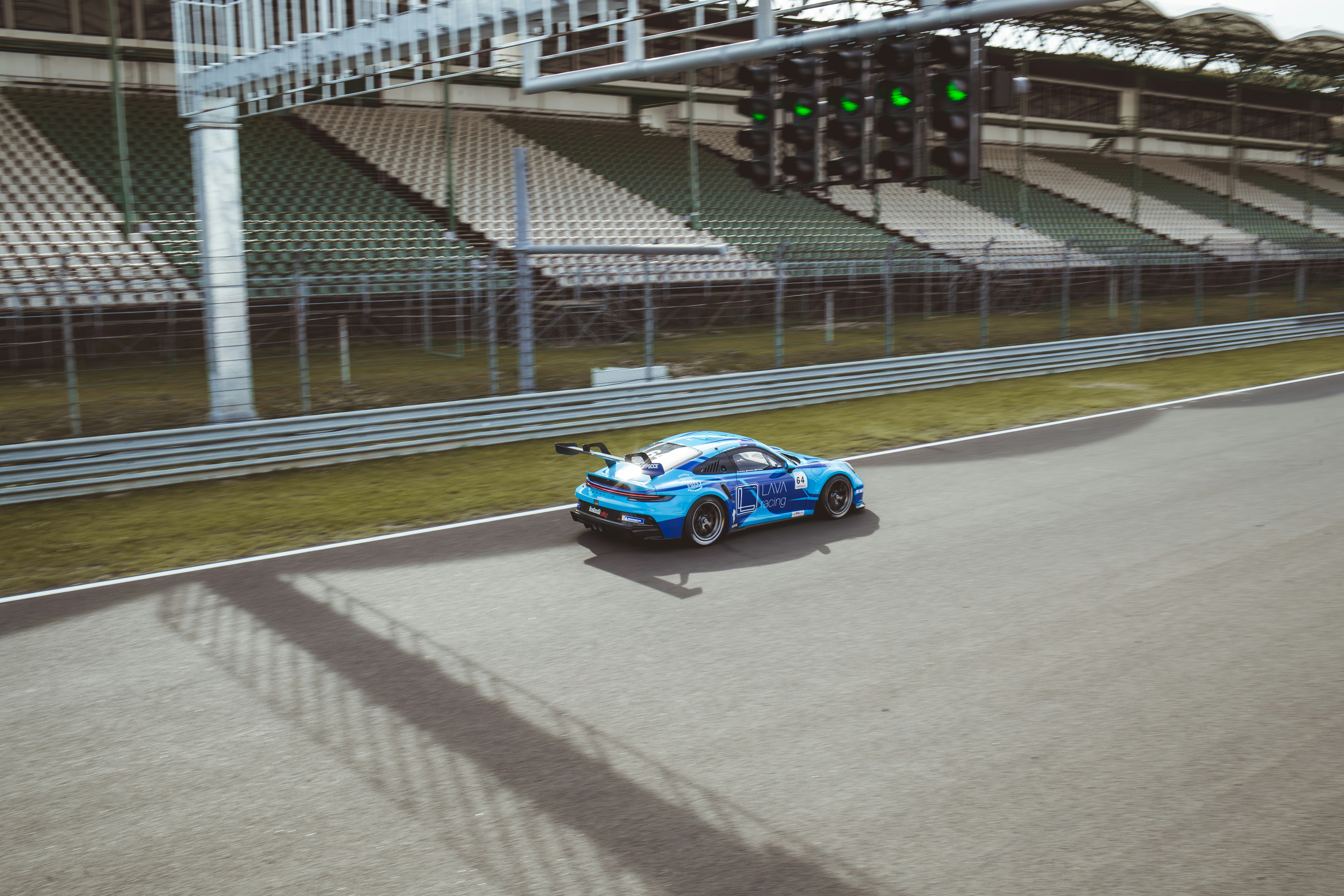 A blue car driving down a race track photo – Free Race car Image on ...