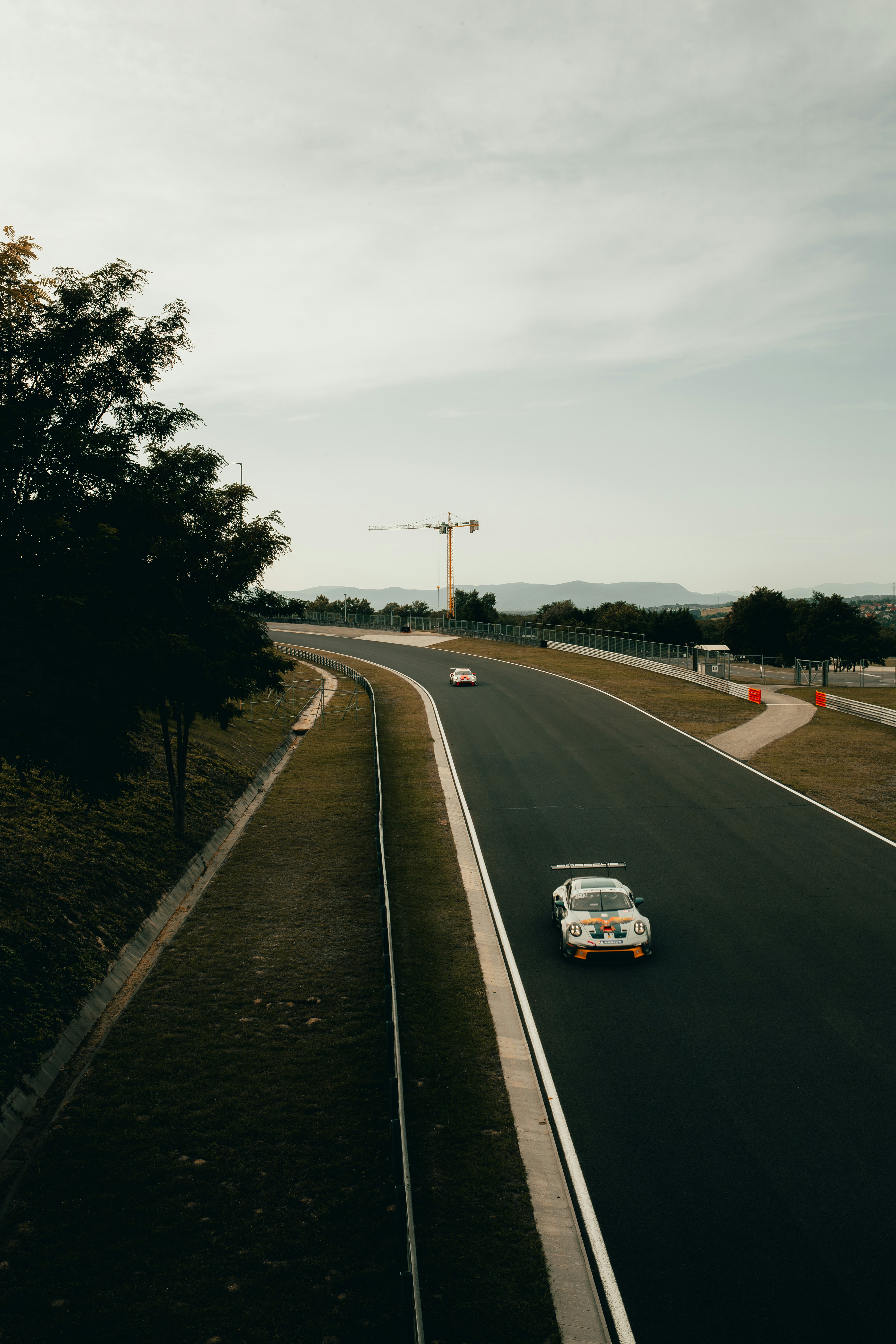 Amidst the scorching Hungarian sun, the Hungaroring racetrack comes alive, a twisting ribbon of asphalt where speed meets precision. Porsche's GT3 Cup race series transforms this circuit into a symphony of roaring engines and burning rubber. Invited to join this adrenaline-fueled spectacle, we witnessed the Hungaroring's mystique unfold, its curves and straights challenging the world's finest drivers. As the cars tore through each lap, the air was charged with anticipation, the grandstands echoing with cheers. Image 11 of 14