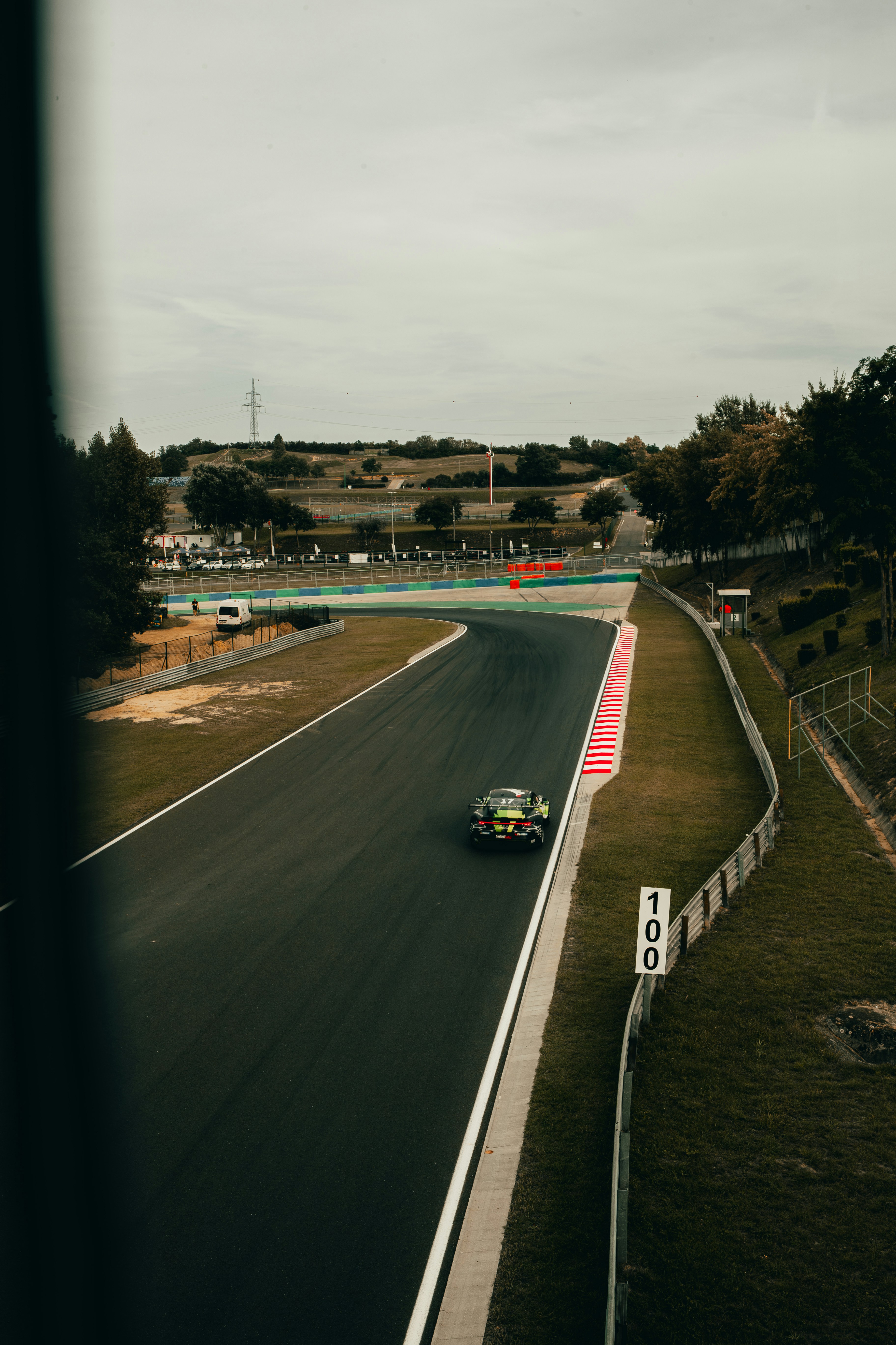 A lone race car carves the bend on a sunlit circuit