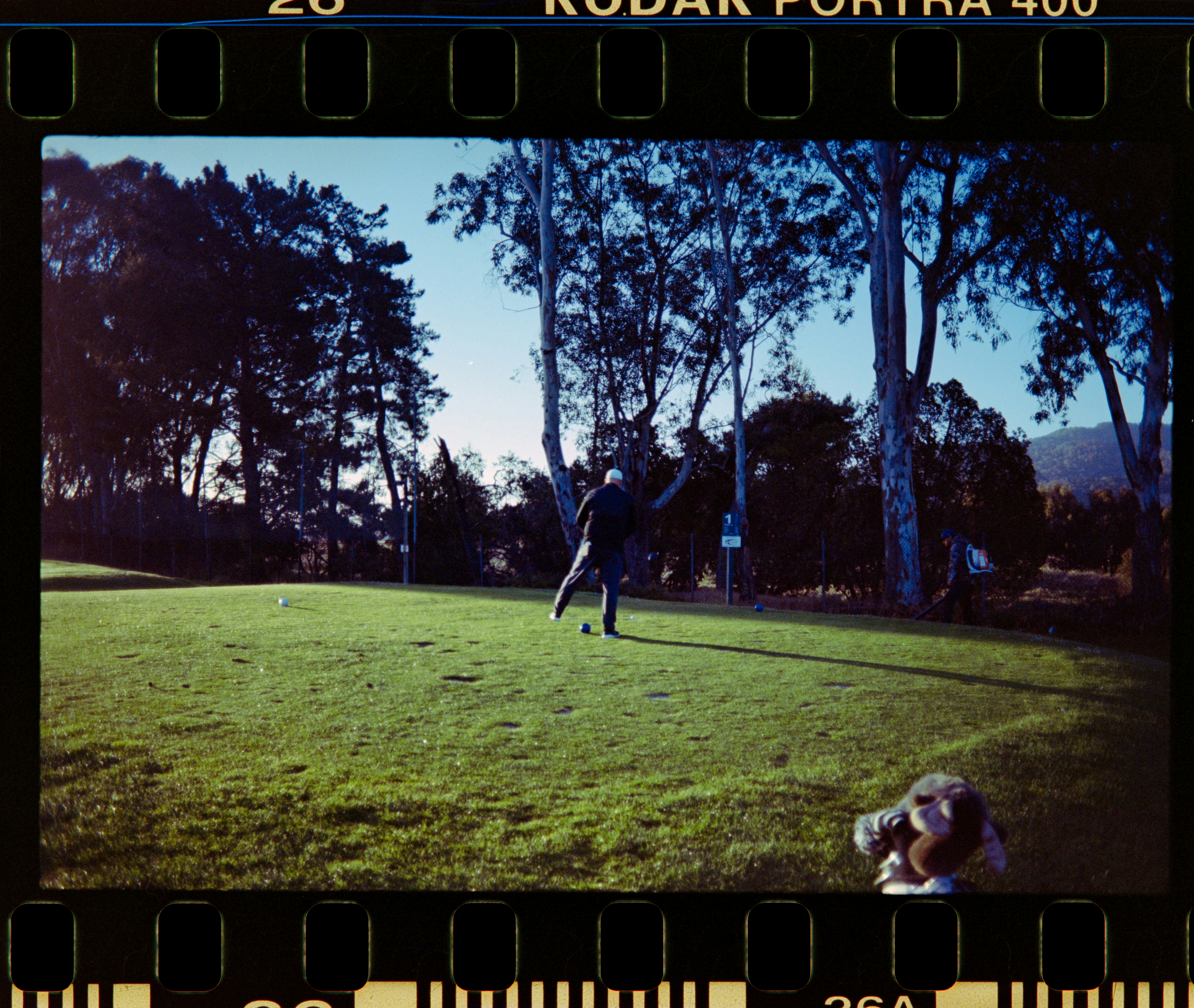 Foot starts the swing: a golfer mid-kick on a sunlit fairway