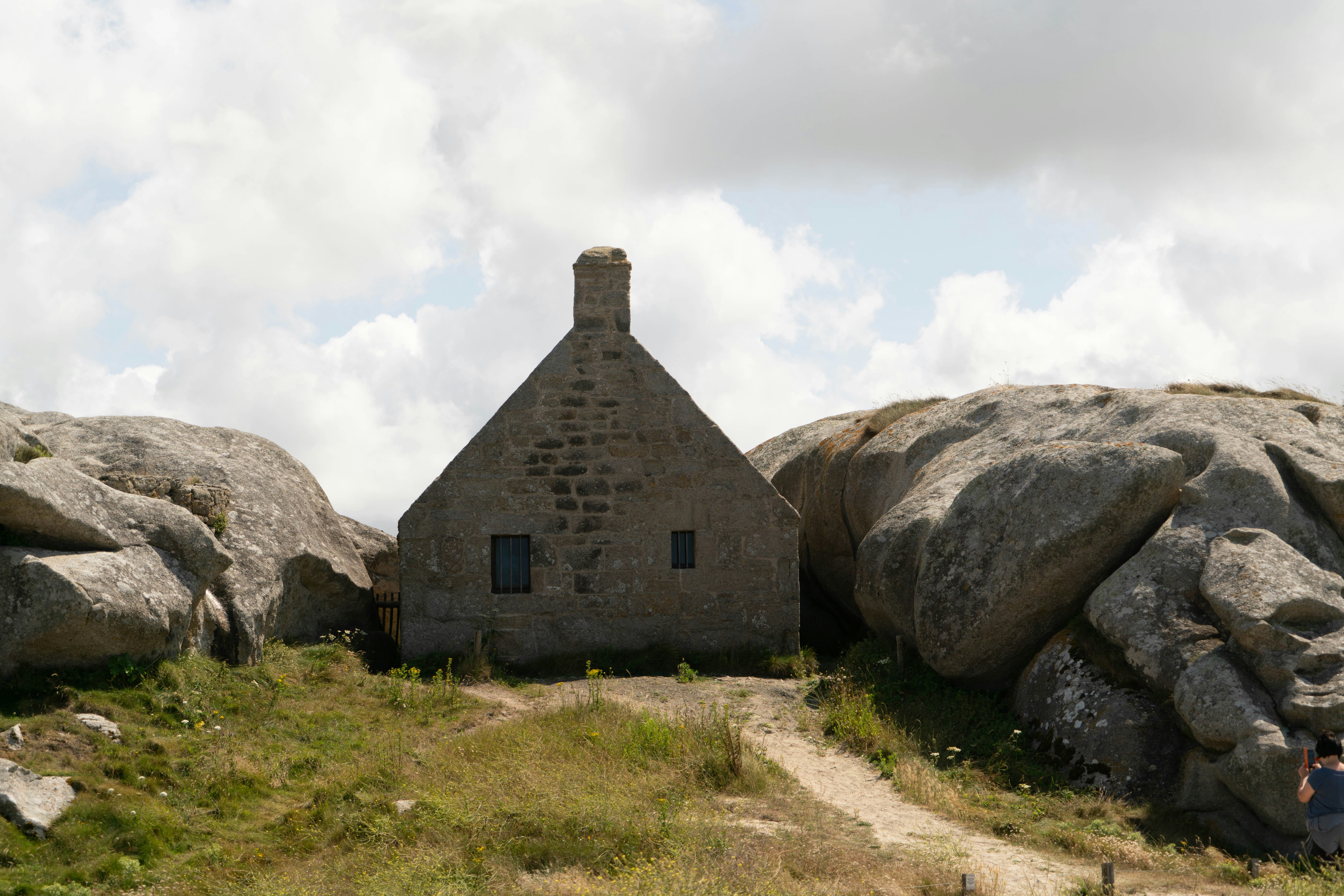 Une maison en pierre entourée de gros rochers et d’herbe photo – Photo ...