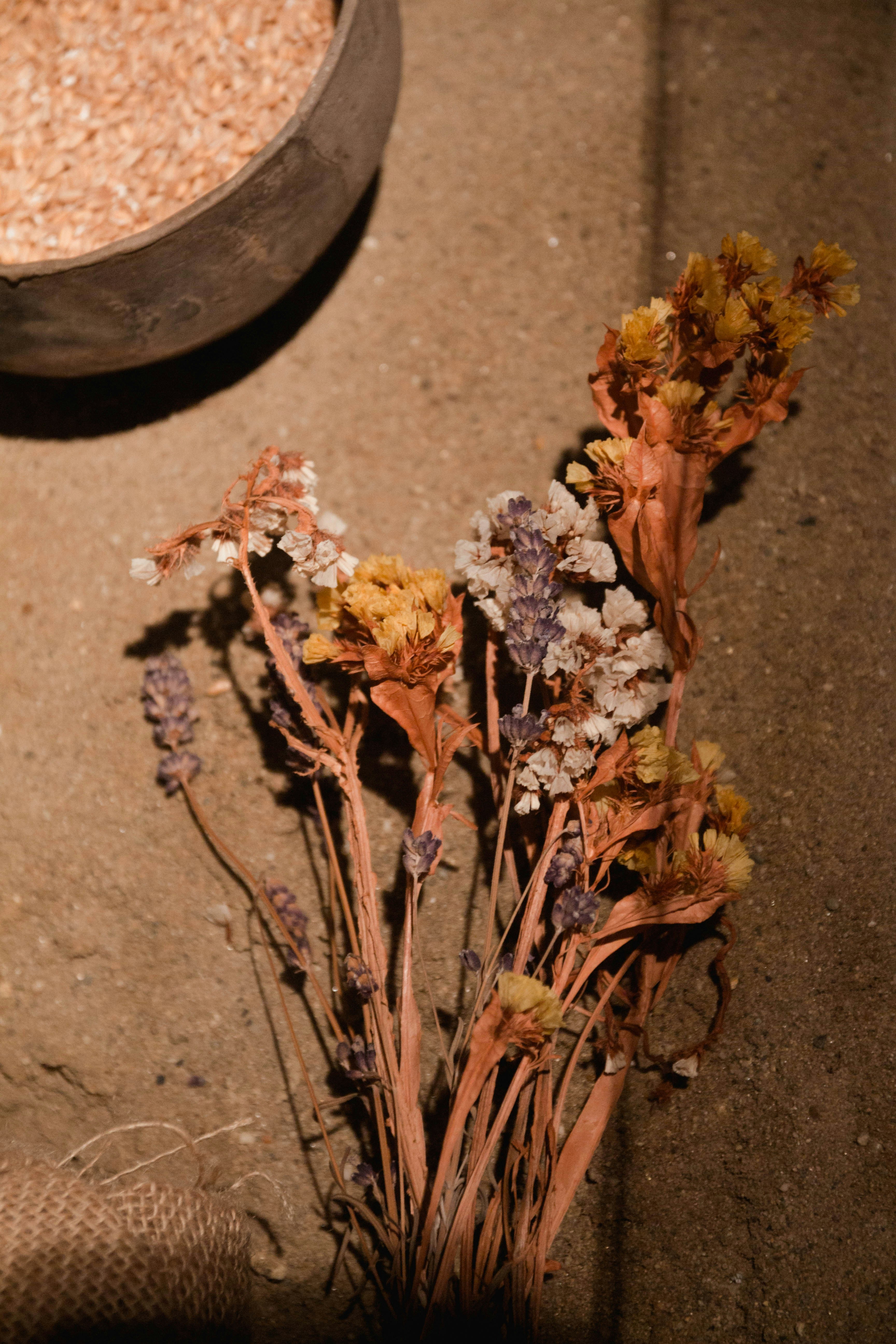 Autumn-tinged dried bouquet on a gritty sidewalk under warm streetlight