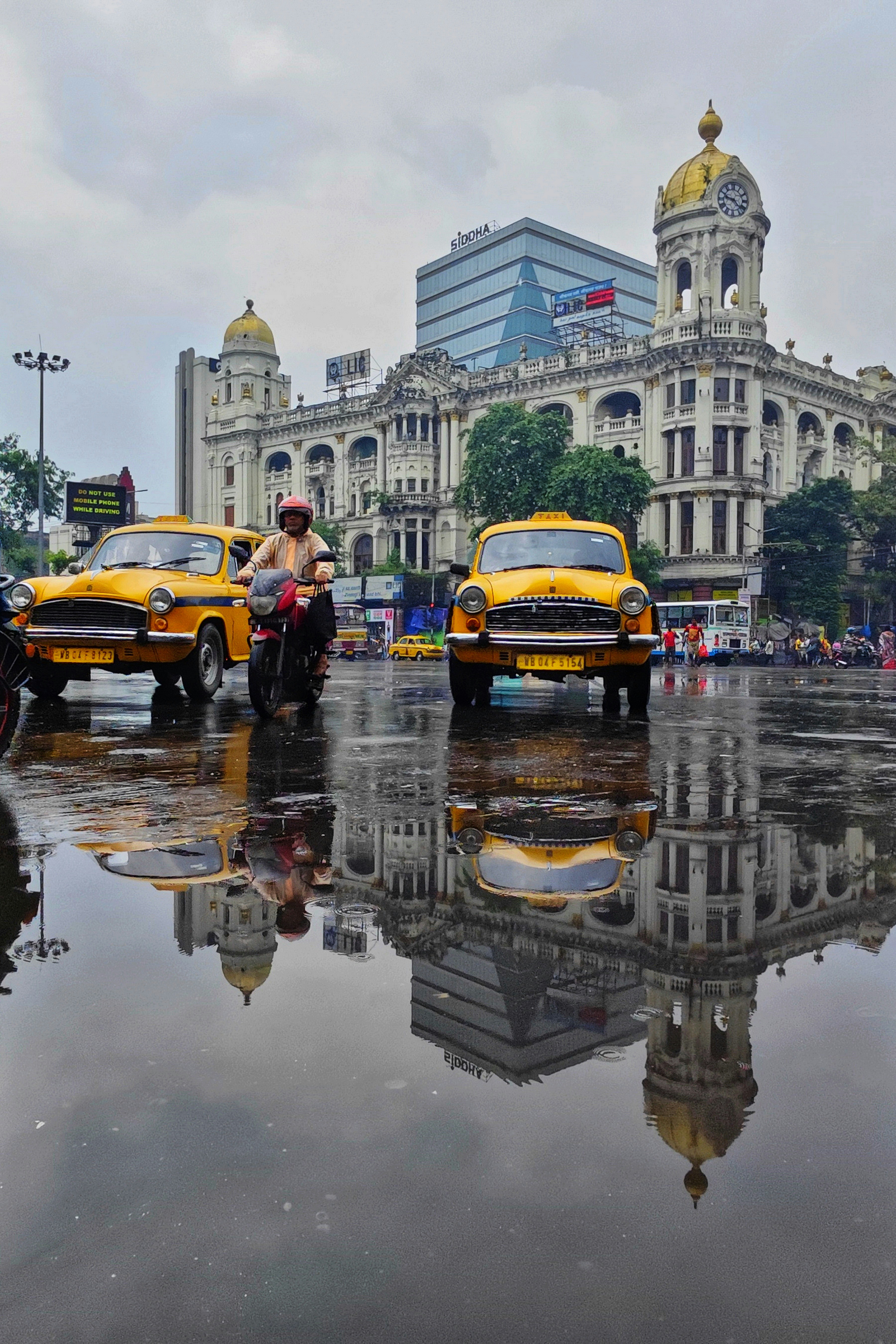 A couple of yellow taxi cabs parked in front of a tall building photo ...