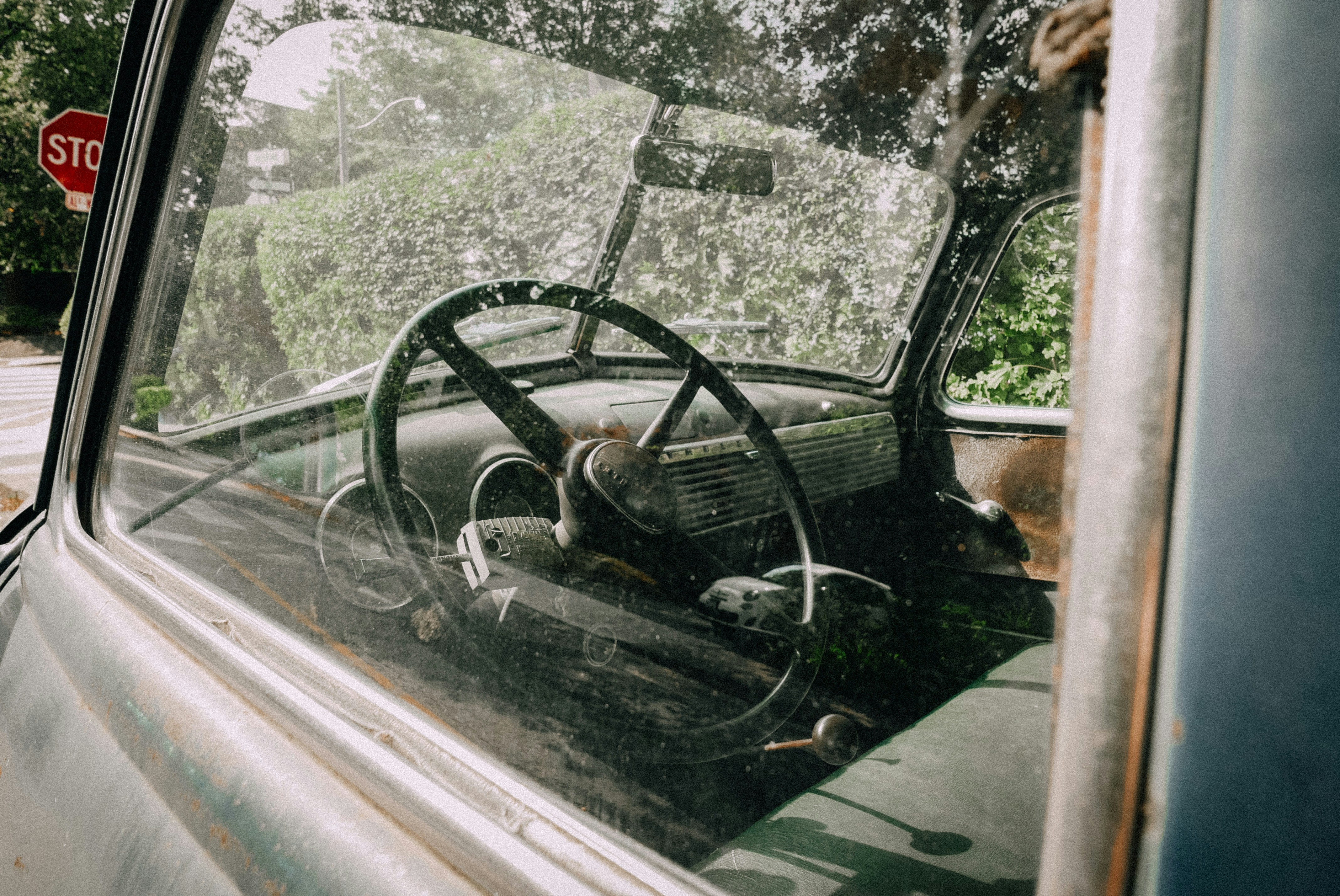 Dust-Kissed Dashboard: A Vintage Car's Quiet Gaze Through a Weathered Window
