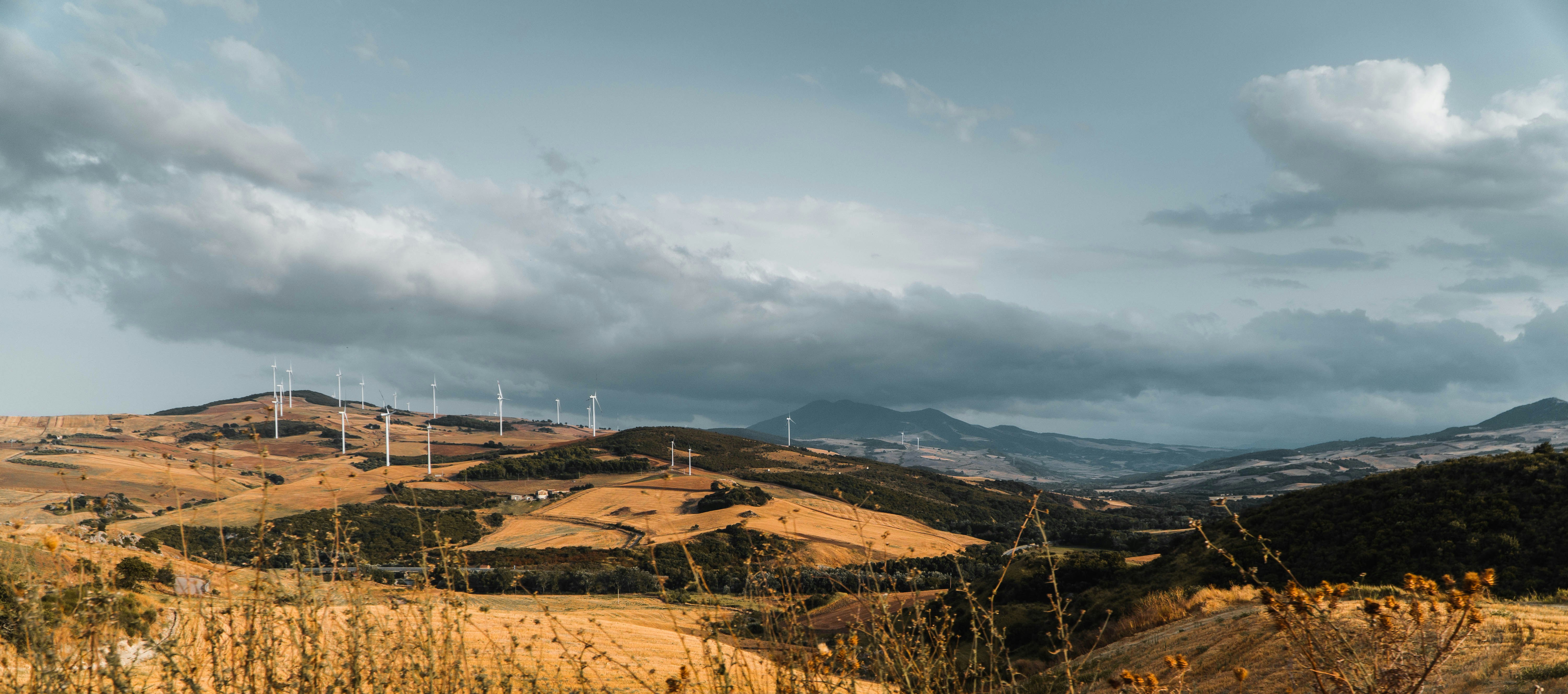 Golden Hills Meet a Row of Wind Turbines Under a Brooding Sky