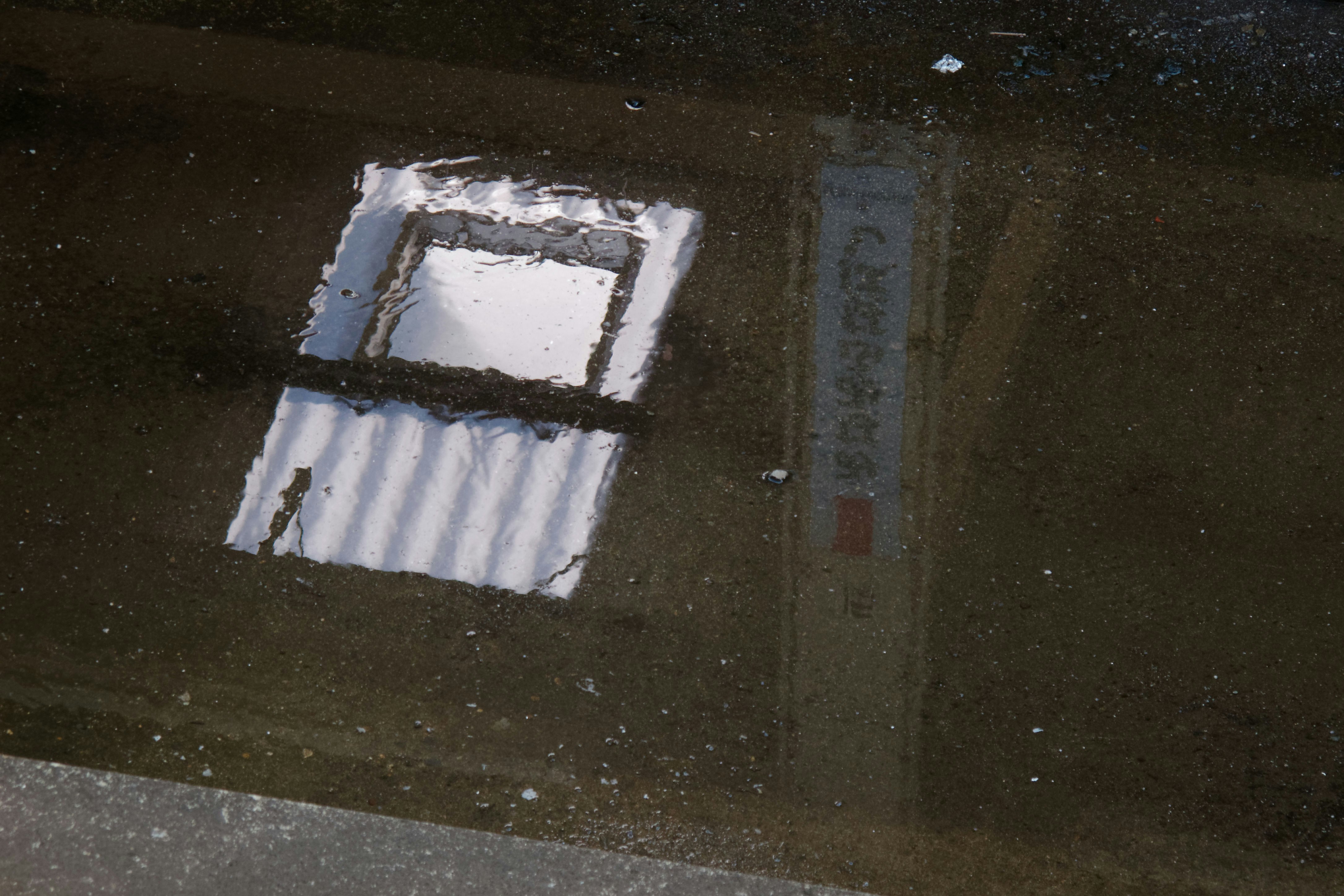 A reflection of a window in a puddle of water photo – Free Puddle Image ...