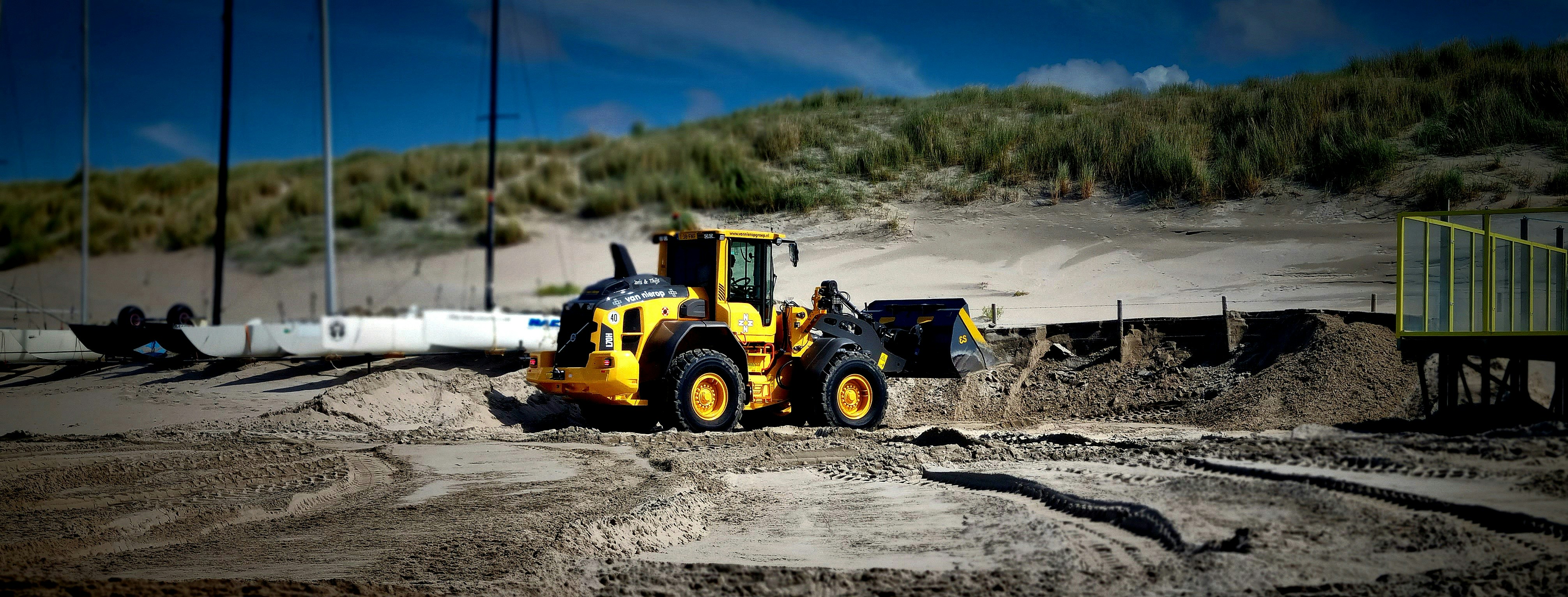 A bulldozer digging through the sand on a beach photo – Free Machine ...