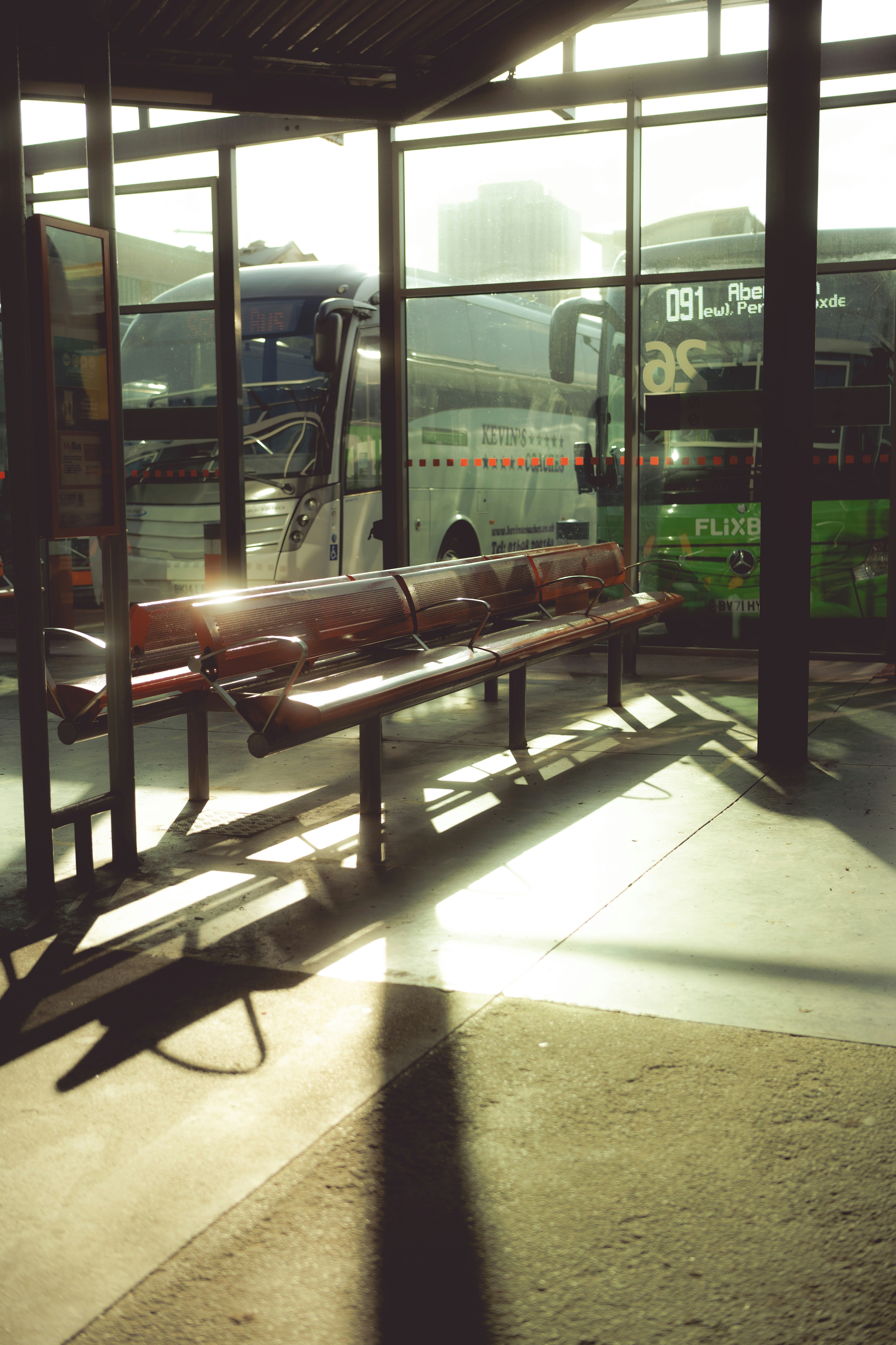 Sunlit Bench Behind Glass: Quiet Transit Geometry
