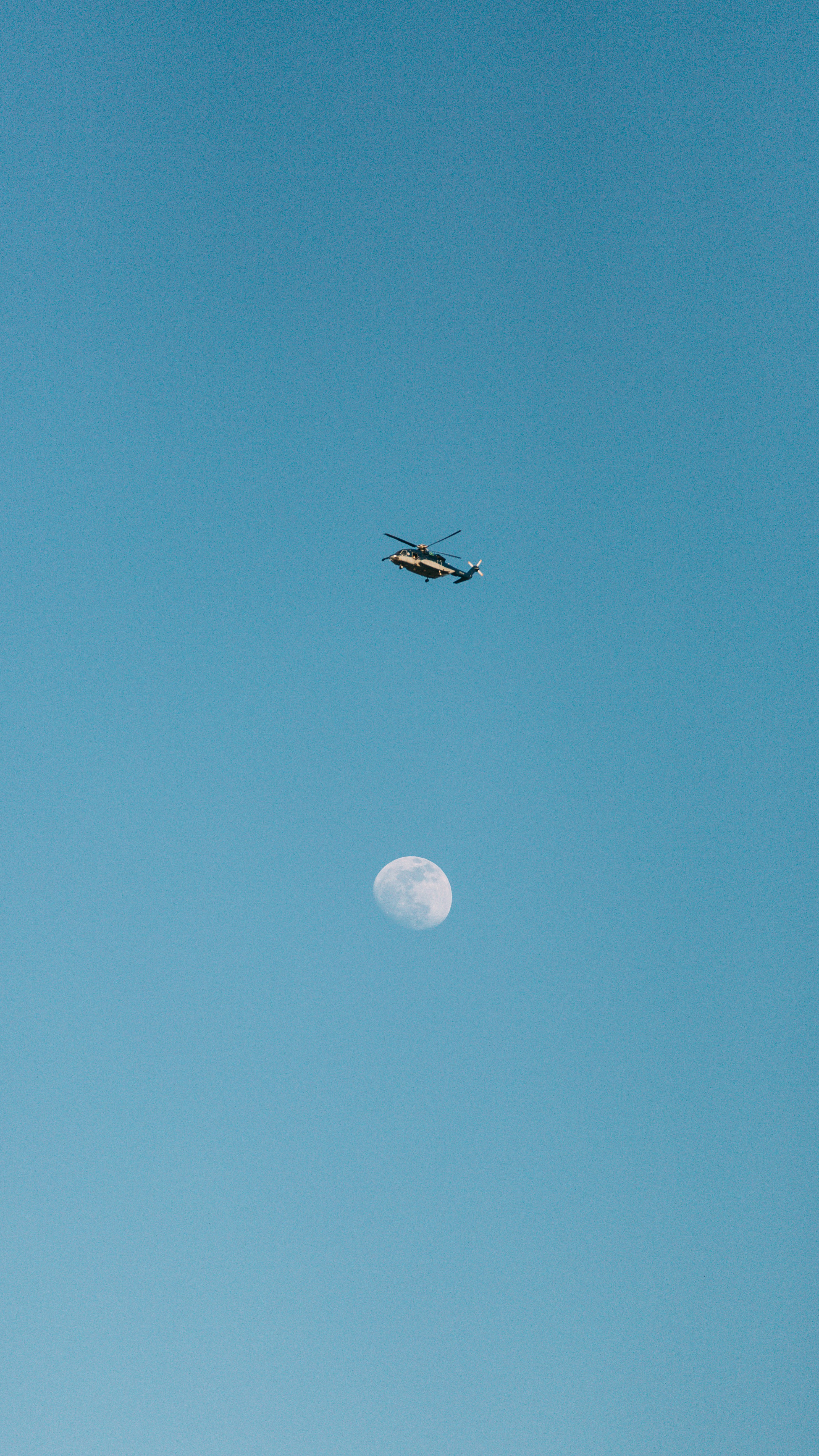 A helicopter flying over the moon in a clear blue sky photo – Free Moon ...