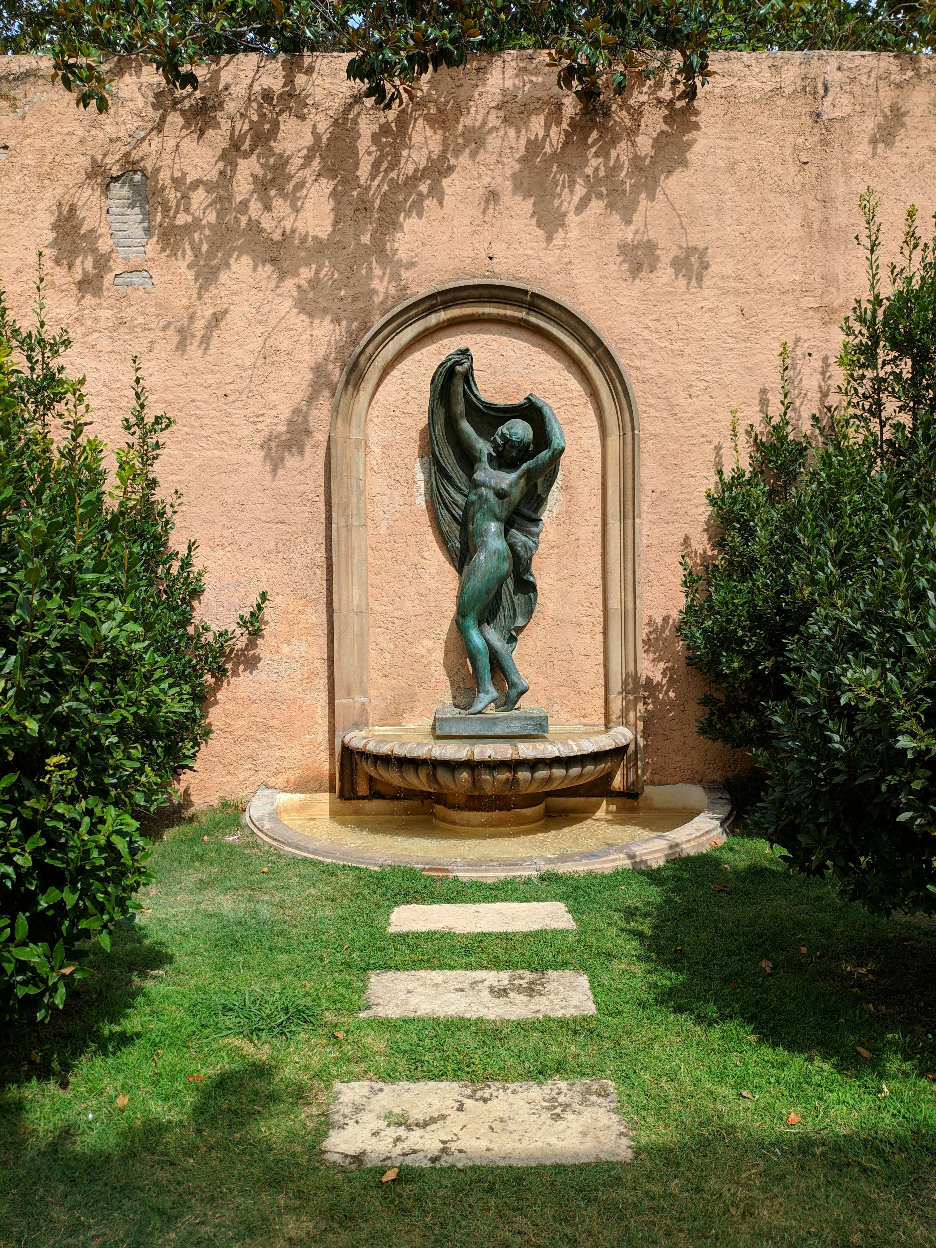 Archside Serenade: Bronze Duo in a Sunlit Garden Fountain