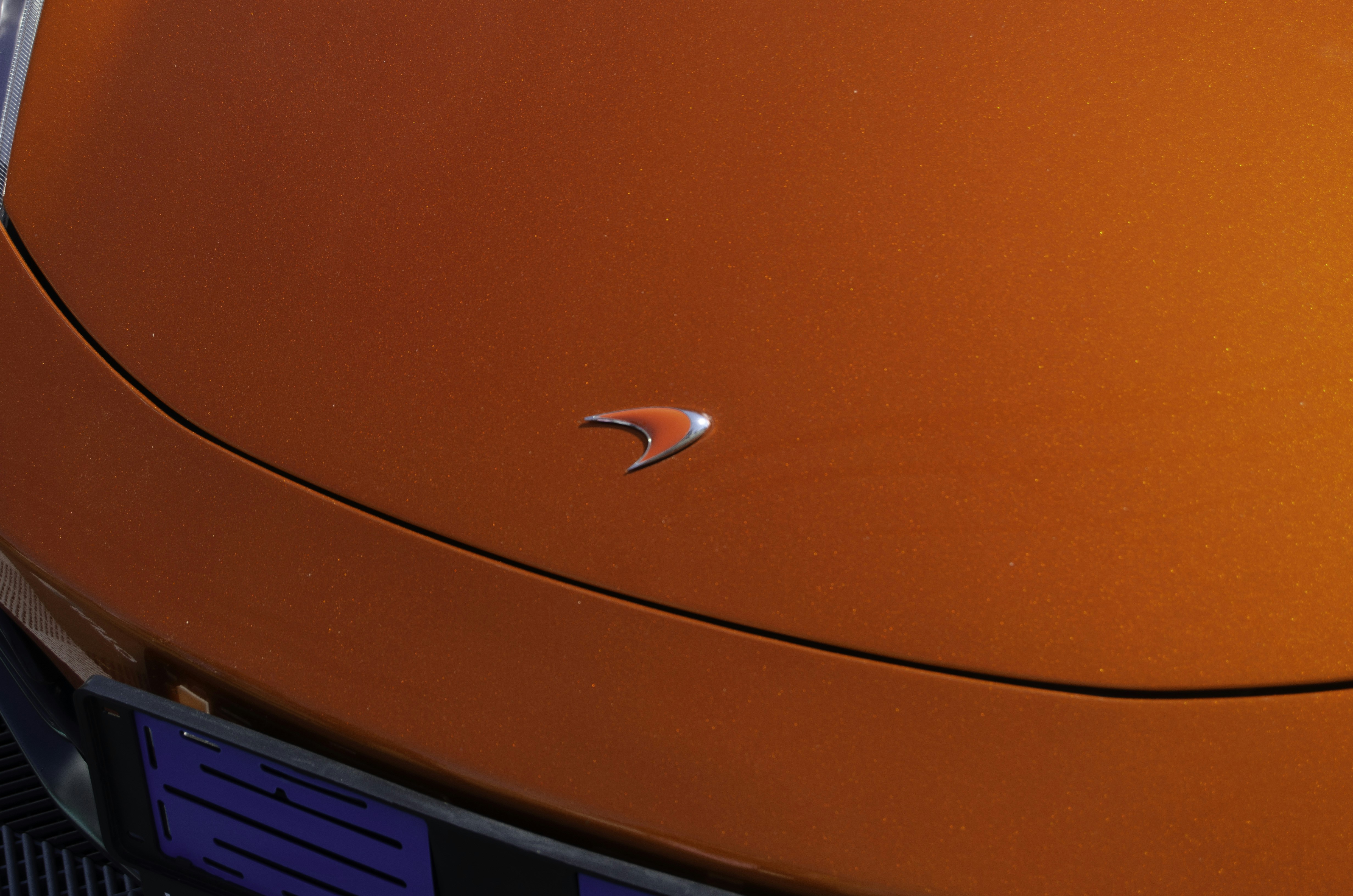 Glossy Ember: The Hood Ornament and Curved Line of a Bright Orange Car