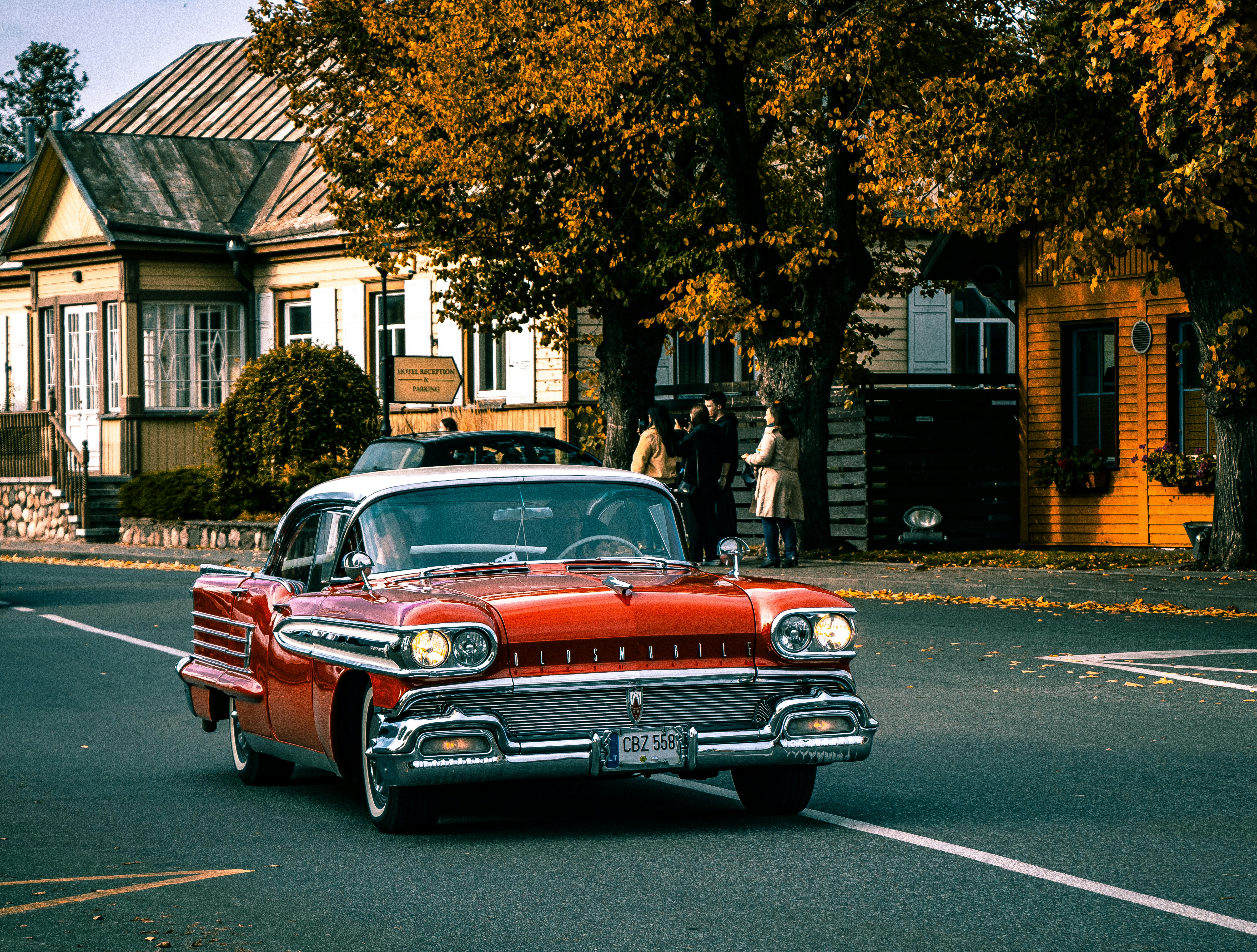 Crimson 1950s Classic on a Leaf-Strewn Autumn Avenue