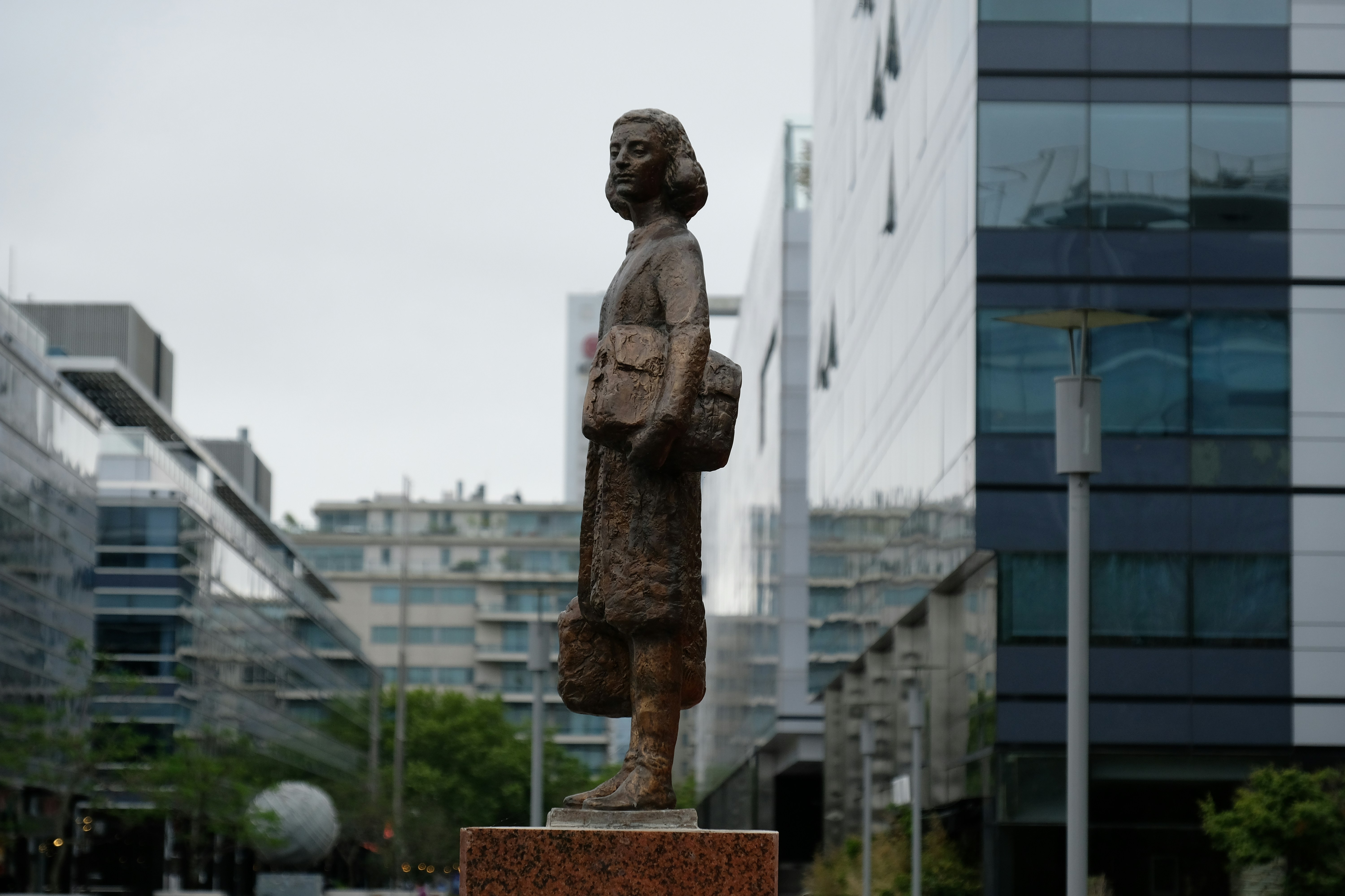 Rust Meets Glass: A Quiet Statue Between Modern Towers