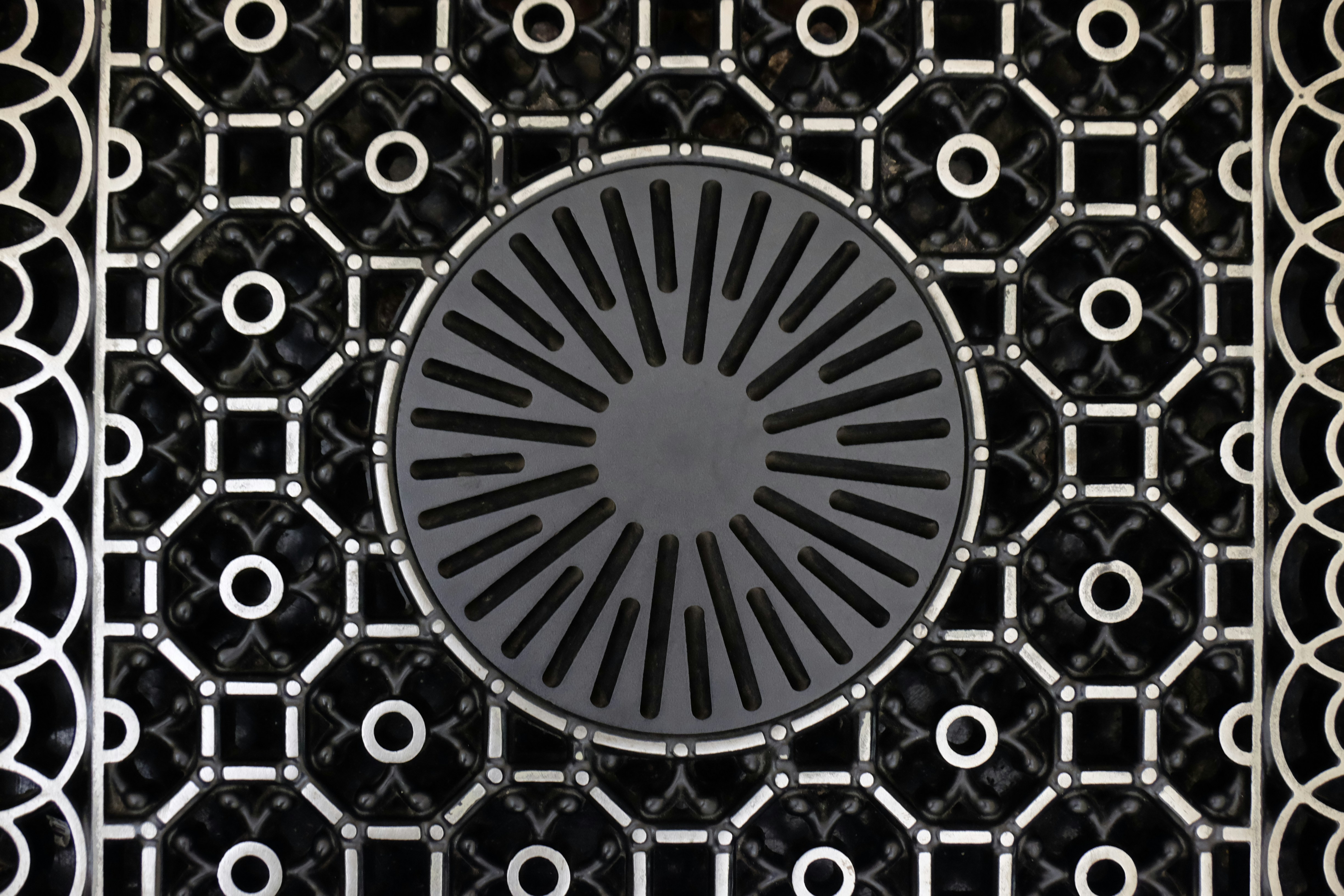 Intricate metal grille with circular and linear patterns creating a symmetrical design.
