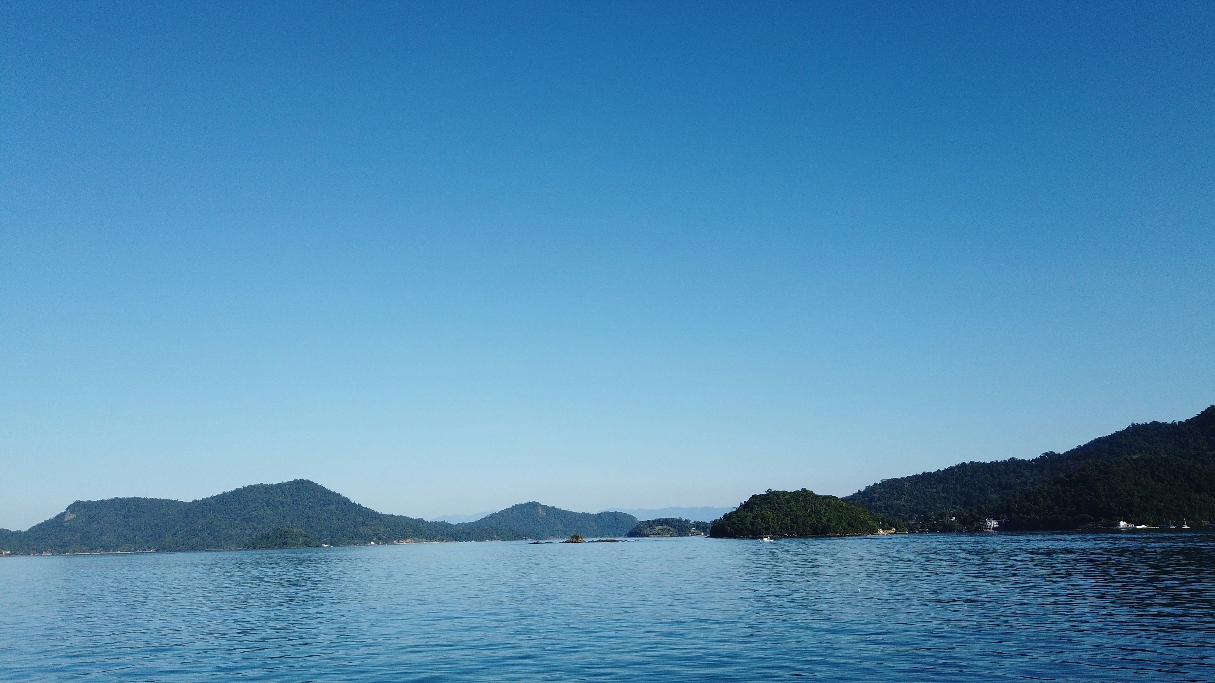 Calm lake reflecting the clear blue sky with distant mountains on the horizon.