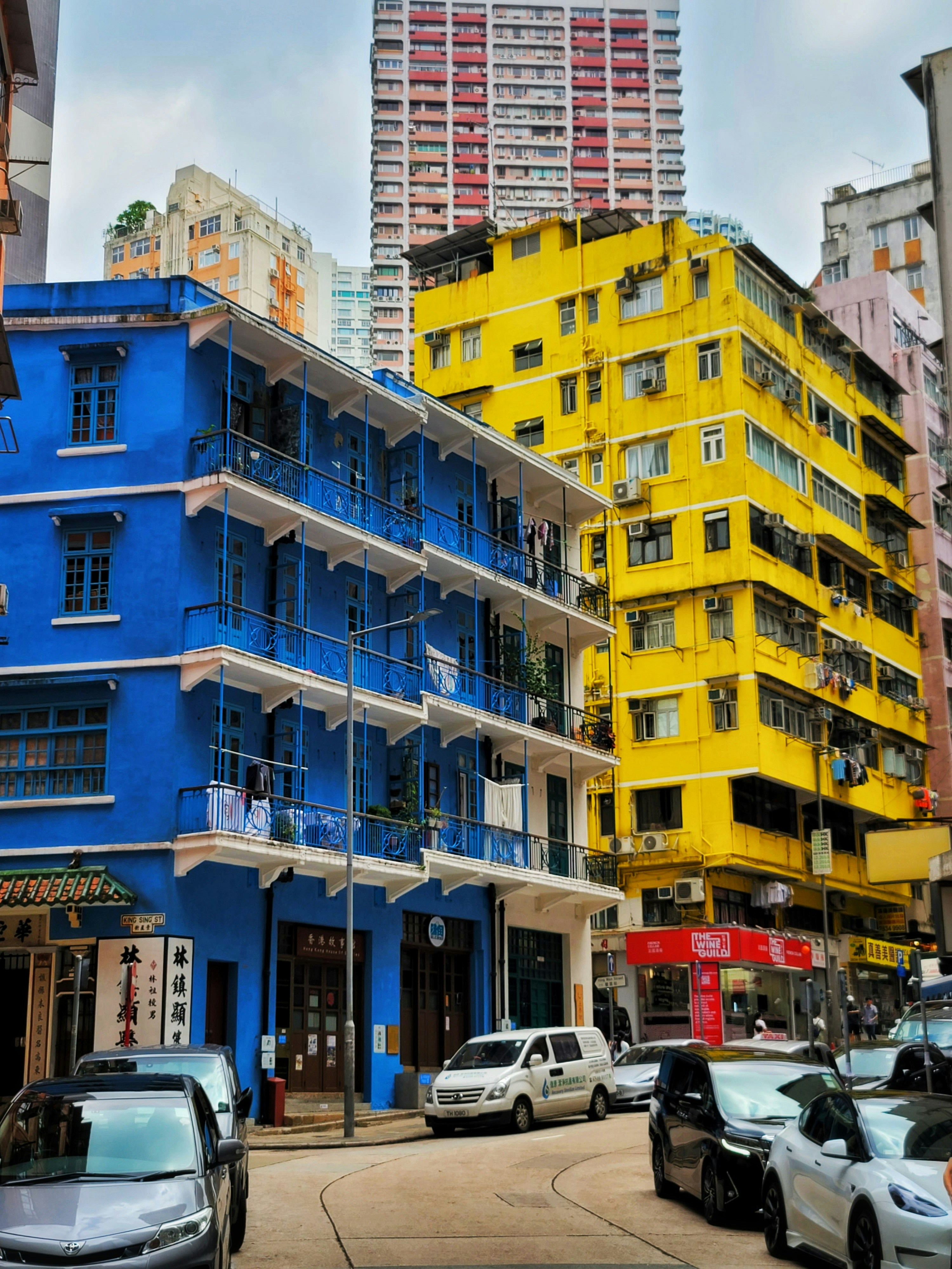 Colorful blue and yellow buildings line a busy street with cars in an urban setting.
