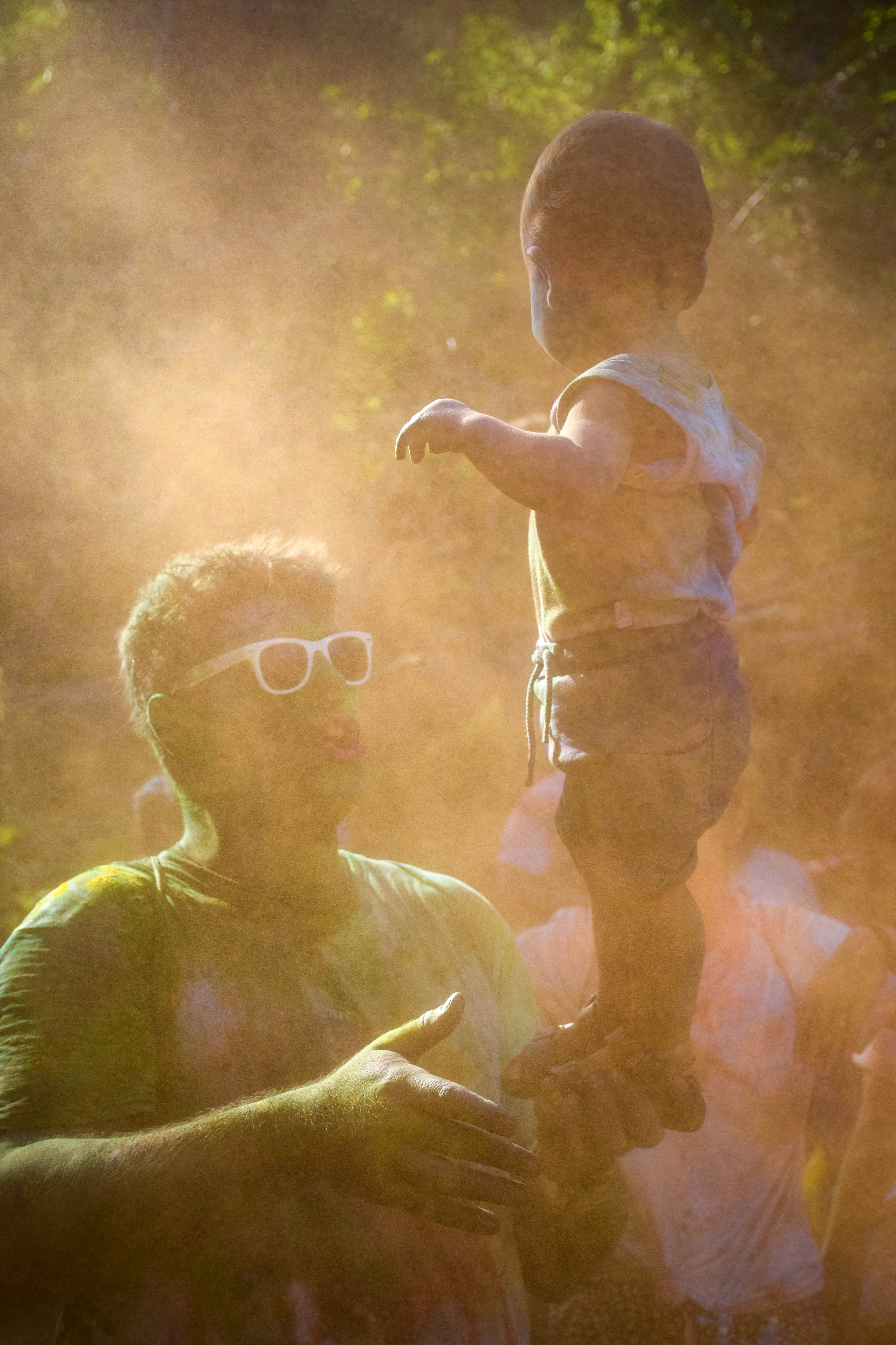 Dust and Lift: A Father Elevates His Child Through a Powder-Hazed Moment