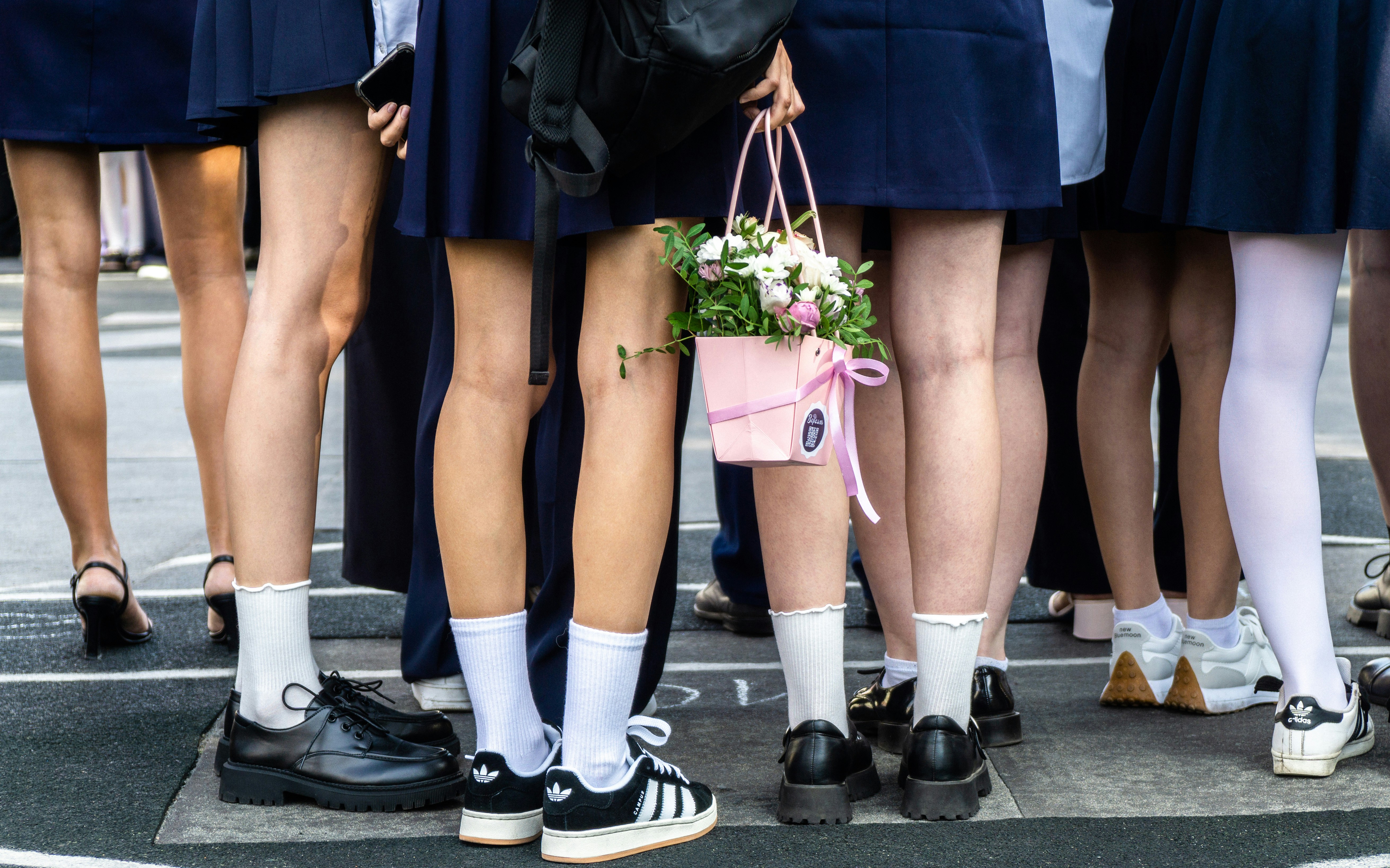 Awaiting Ceremony: A Row of Uniformed Shoes and a Pink Bouquet