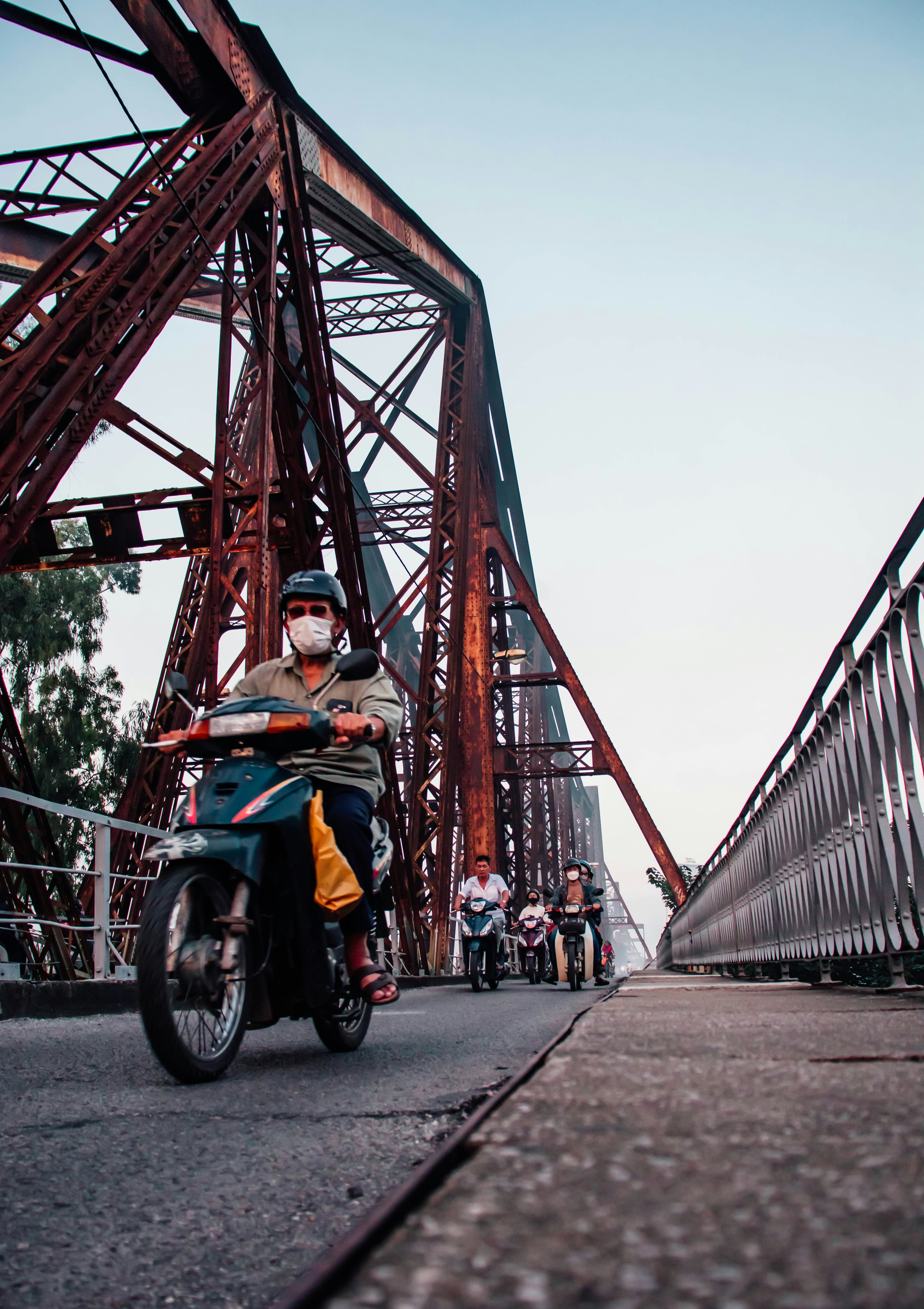 A person riding a motorcycle on a bridge photo – Free Long bien bridge ...
