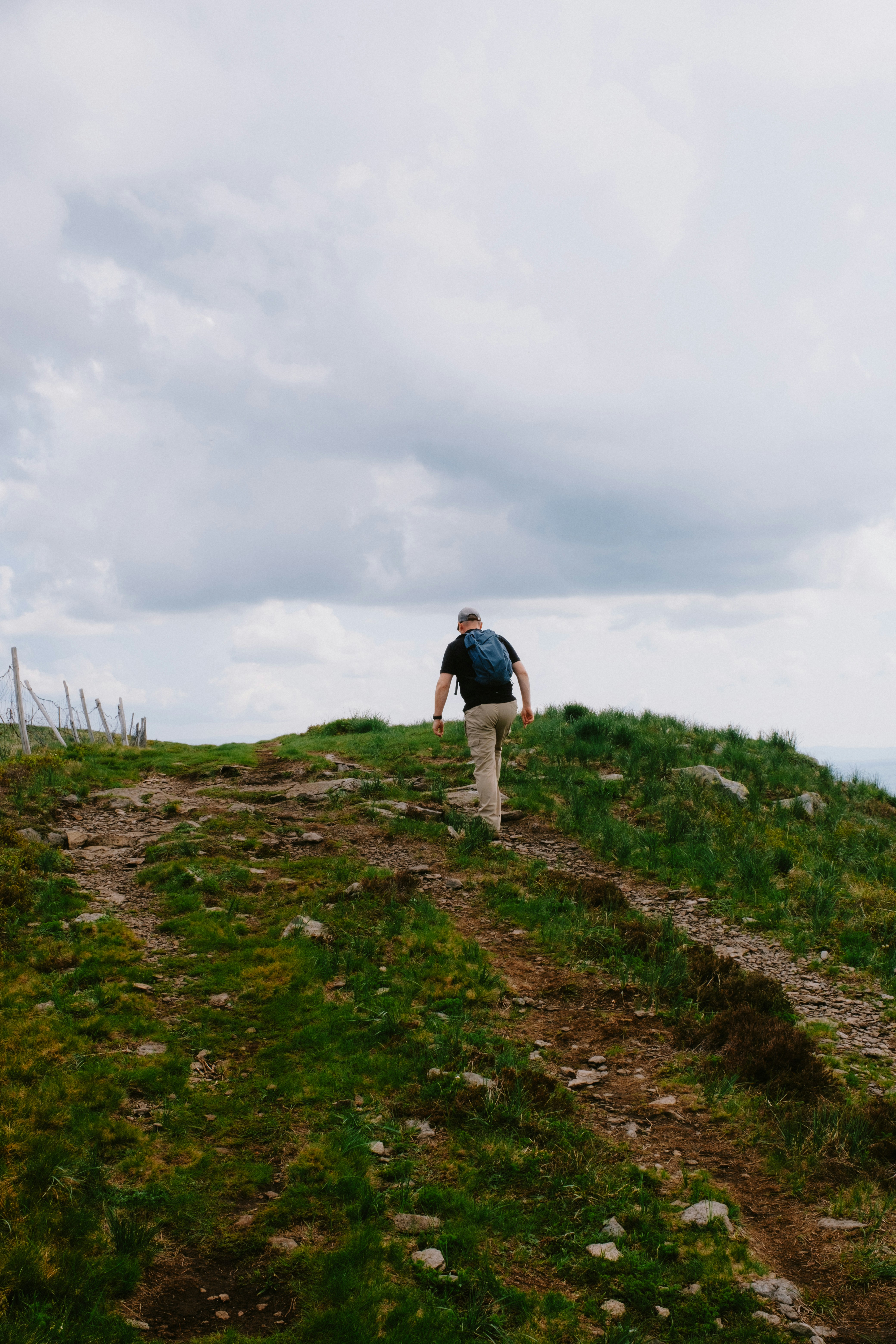 A man walking up a hill on a cloudy day photo – Free Land Image on Unsplash