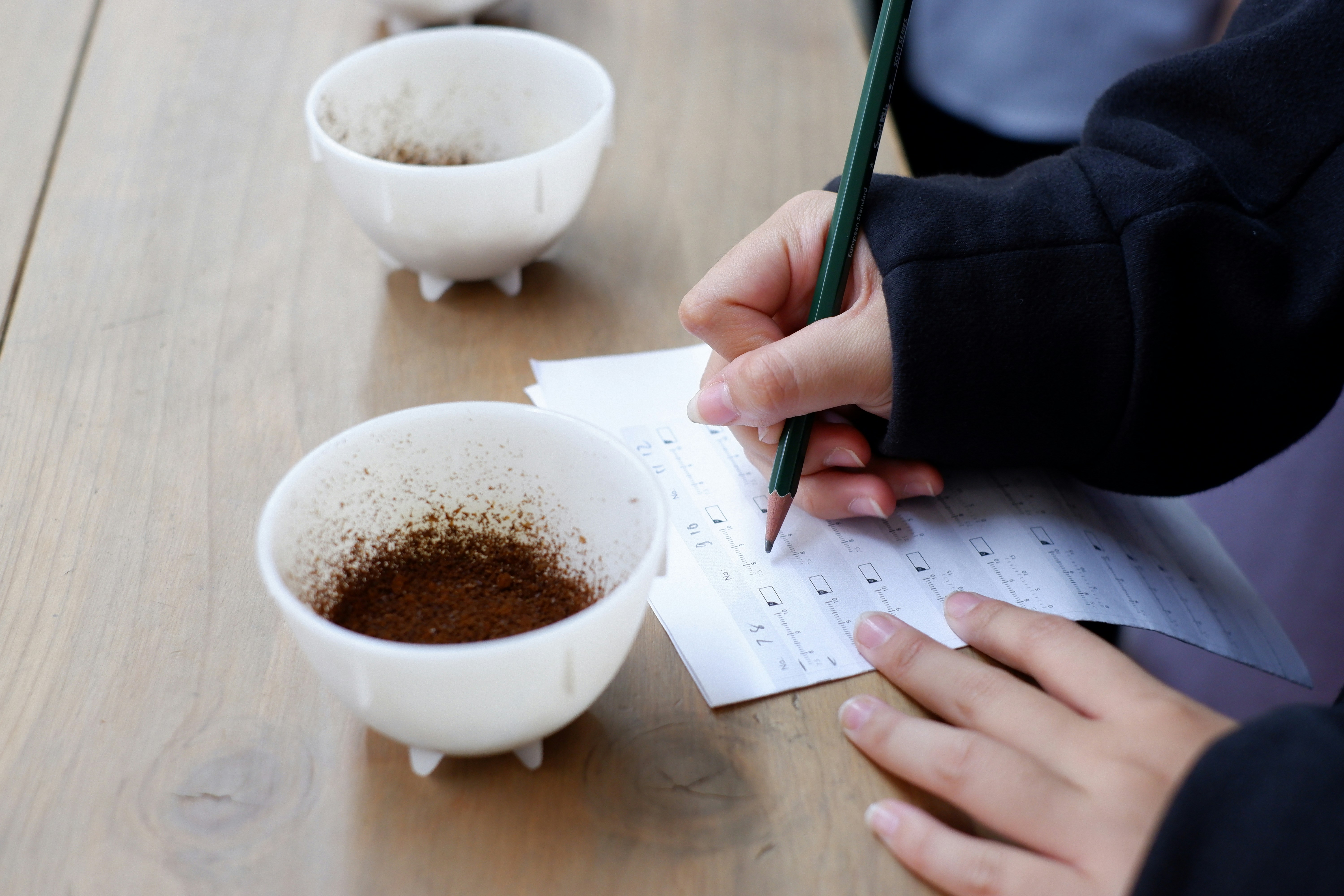 A person writing on a piece of paper next to two cups of coffee photo ...