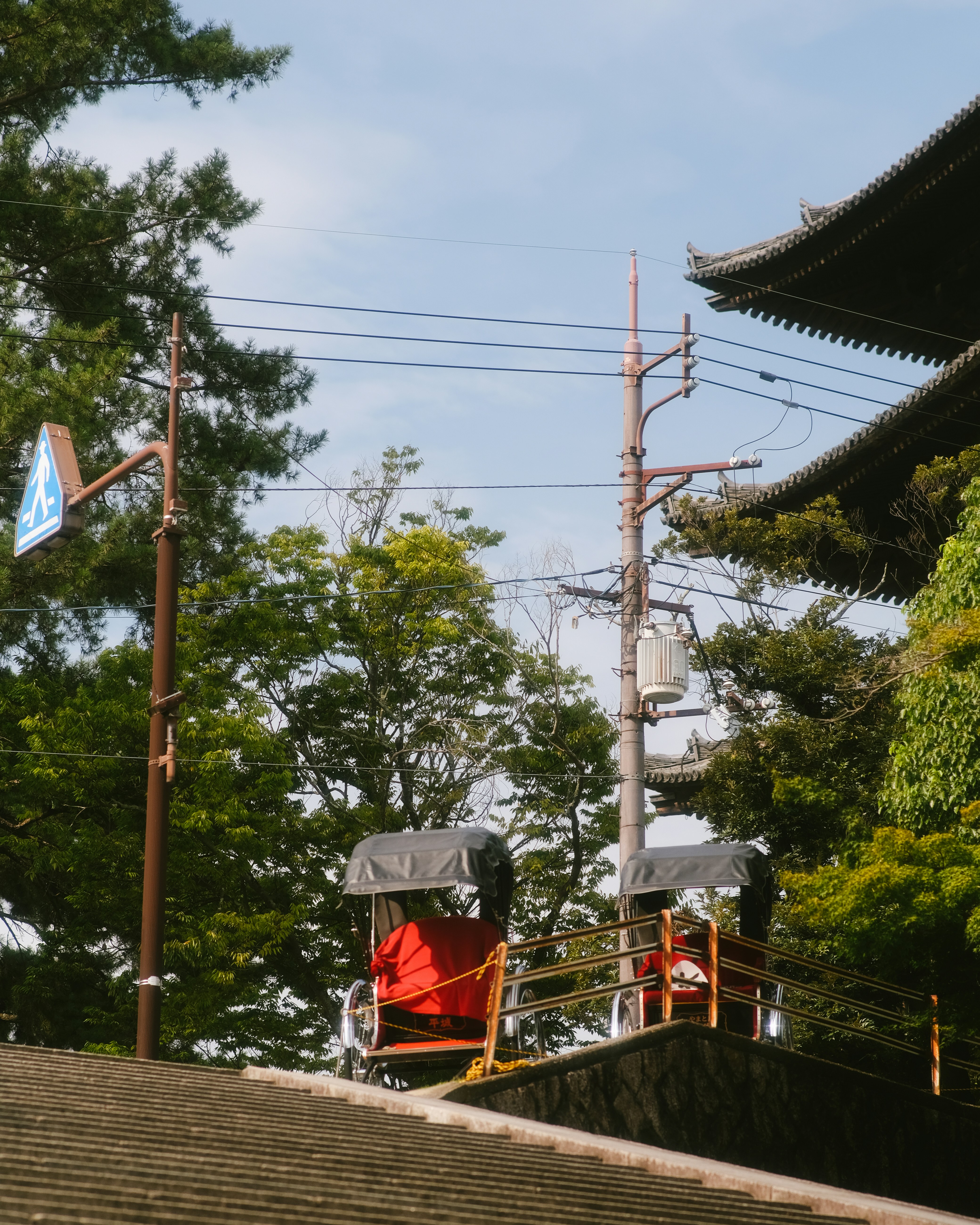 Red-robed figures on a temple terrace beneath a web of wires