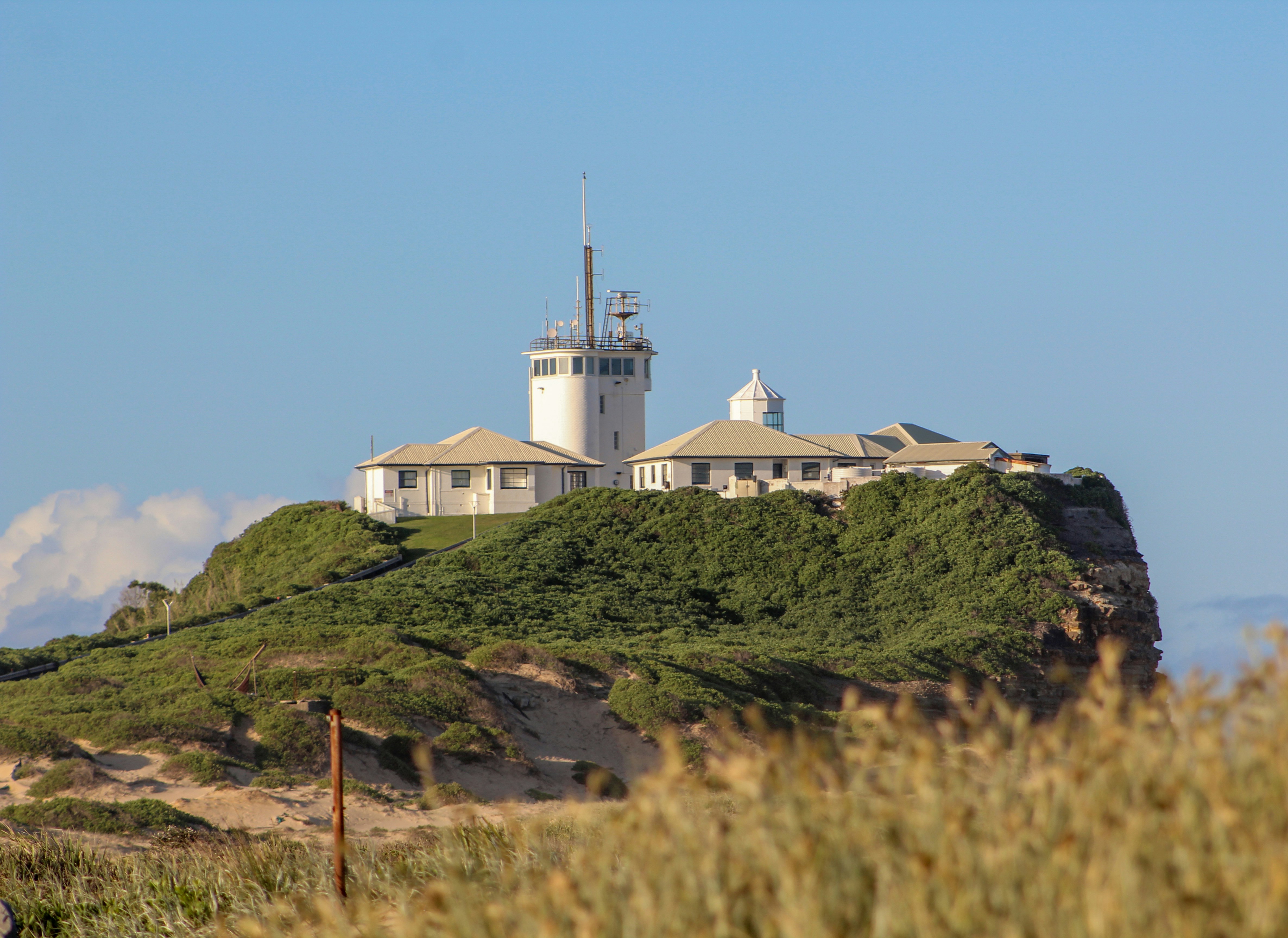 Beacon on the Bluff: A Coastal Lighthouse Complex Against a Clear Sky