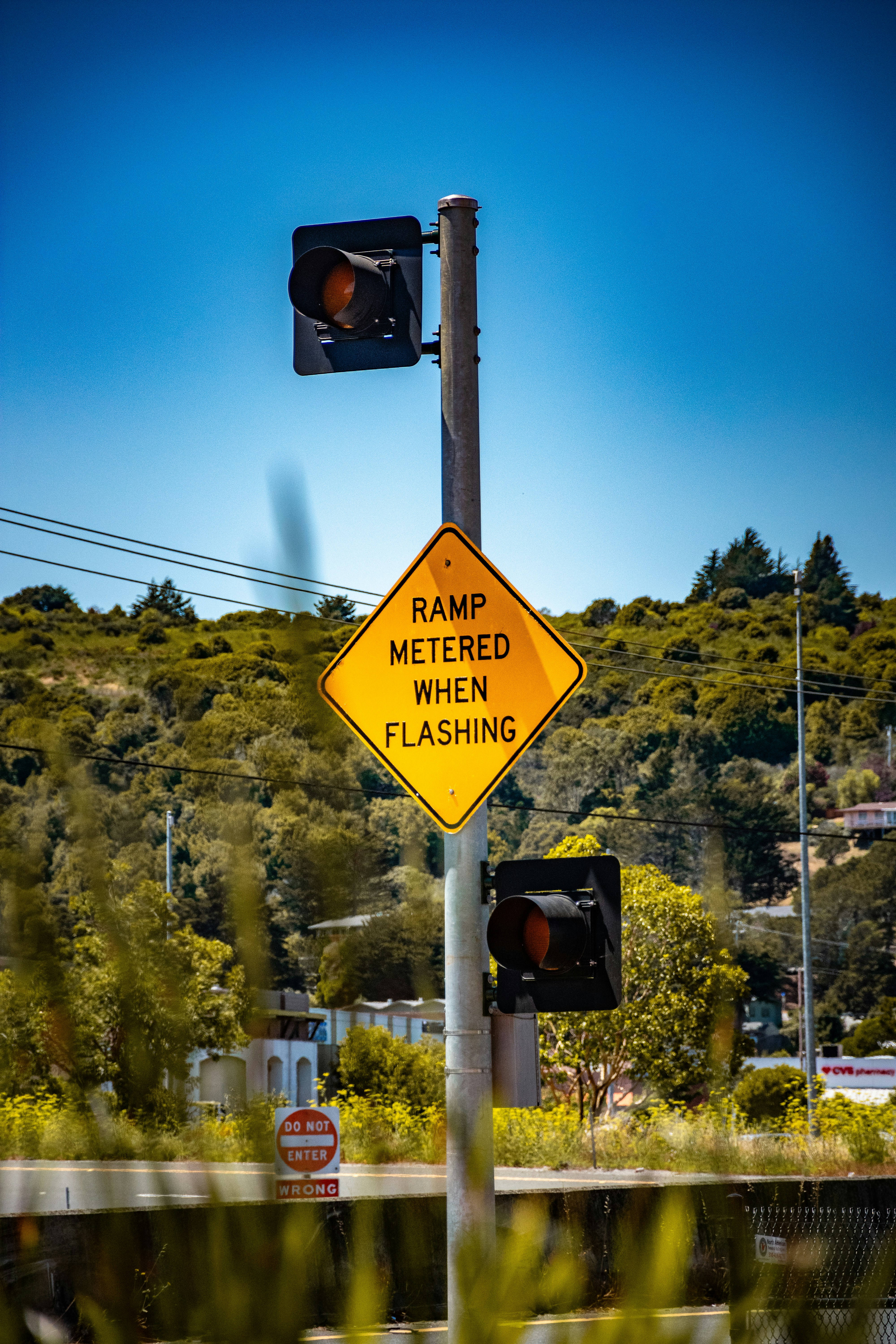 Signal in the Sunlit Valley: A Yellow Warning Diamond Above the Quiet Street