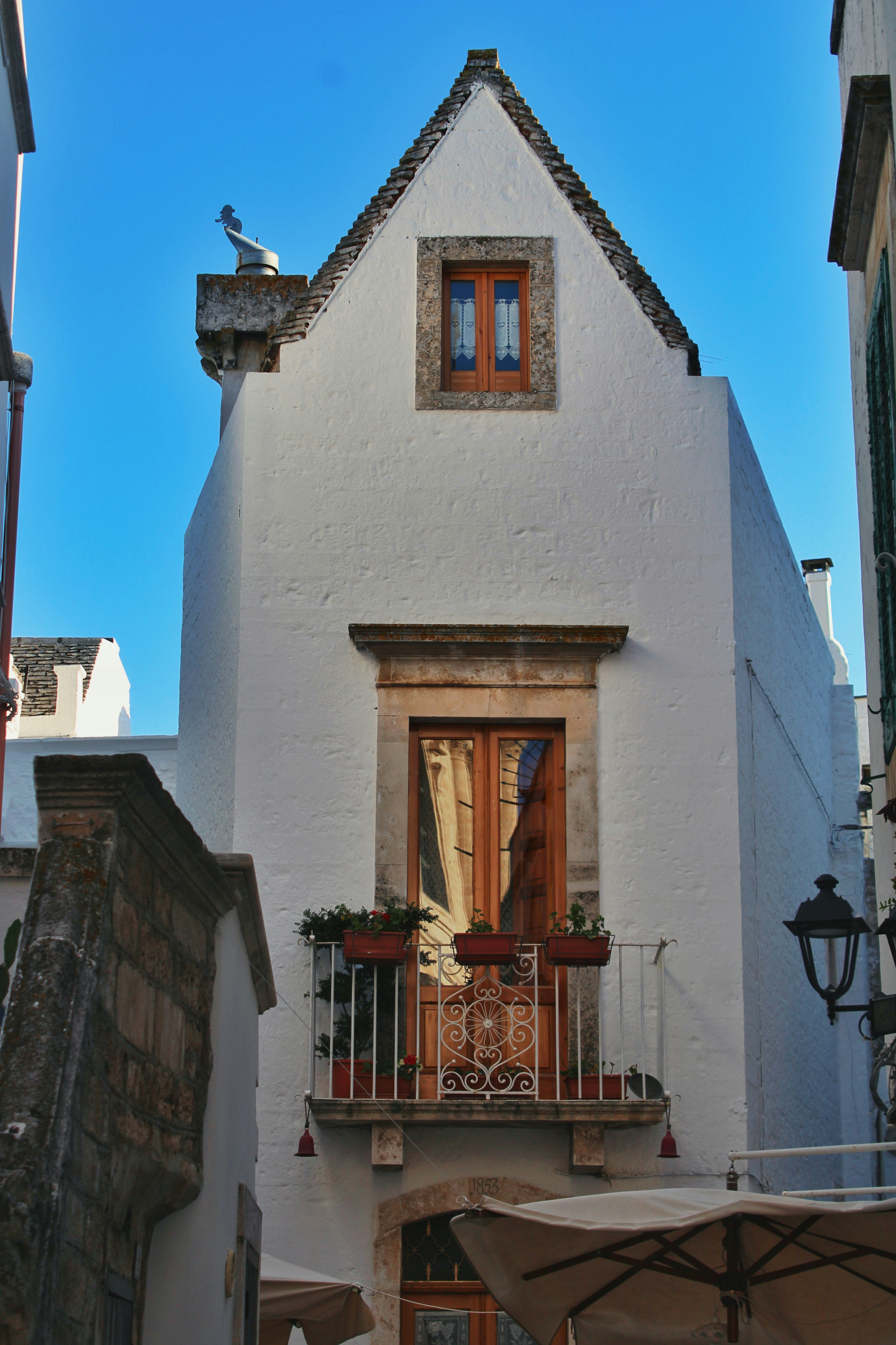Whitewashed Townhouse with a Flower-Filled Balcony Under a Crisp Blue Sky